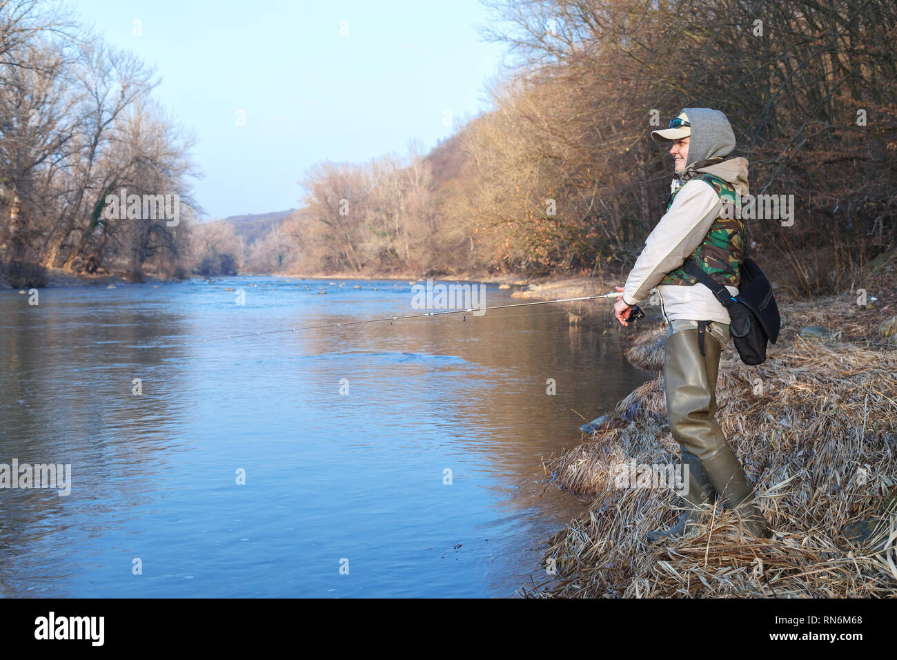 A young attractive woman catches fish with a spinning, standing on the ...