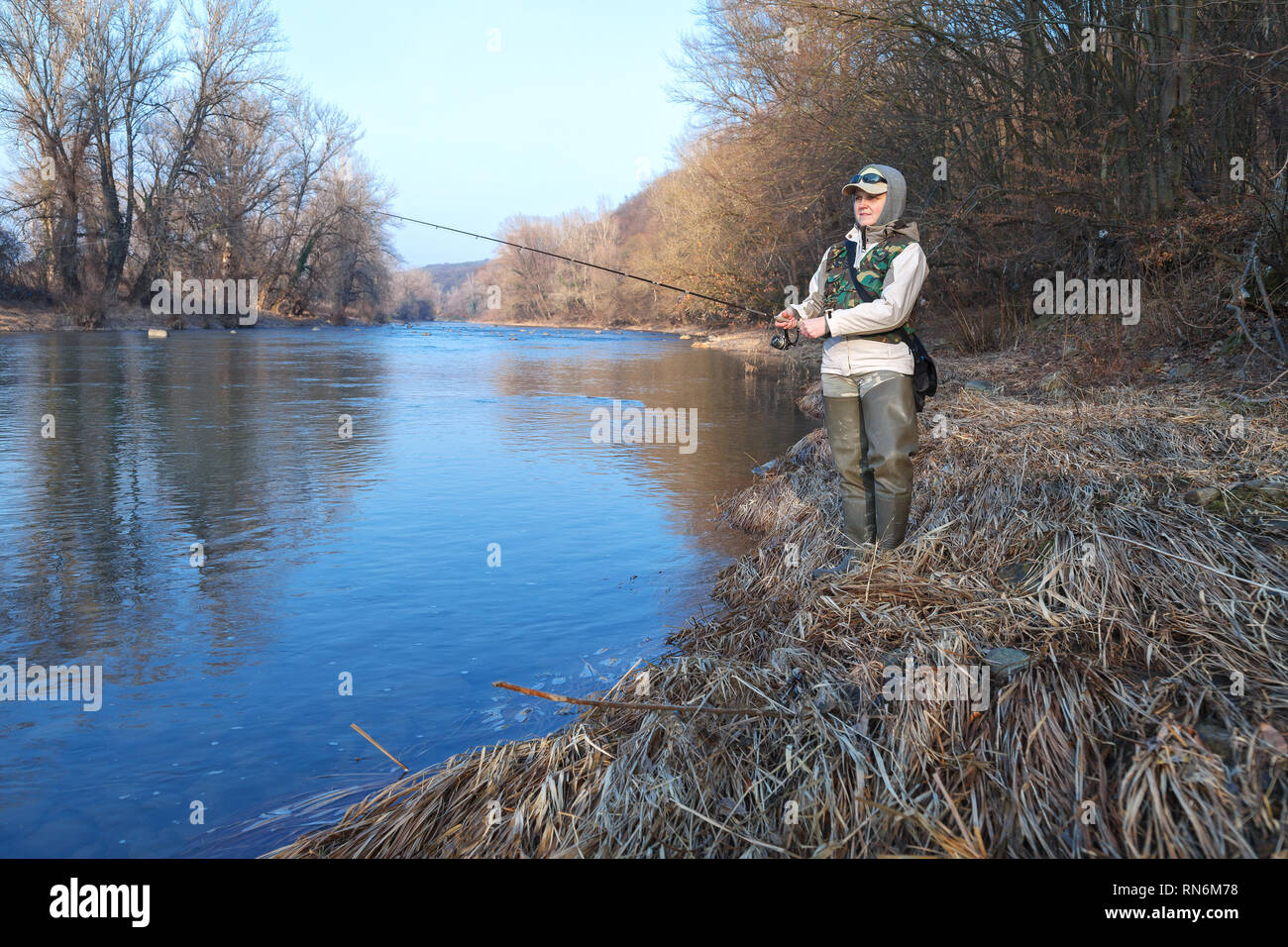 A young attractive woman catches fish with a spinning, standing on the ...
