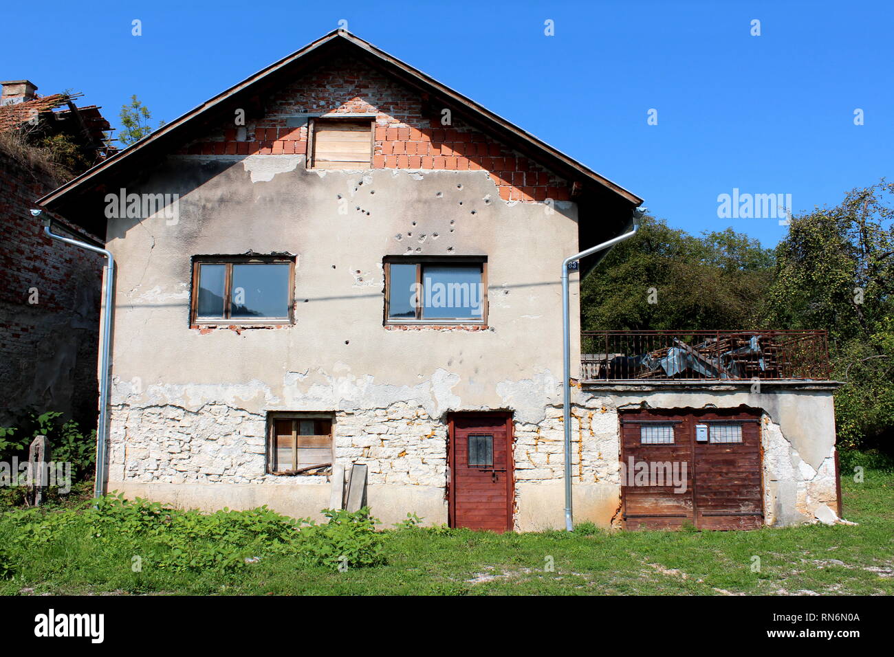 Suburban family brick house with attached garage and cracked damaged facade from shrapnels and ...