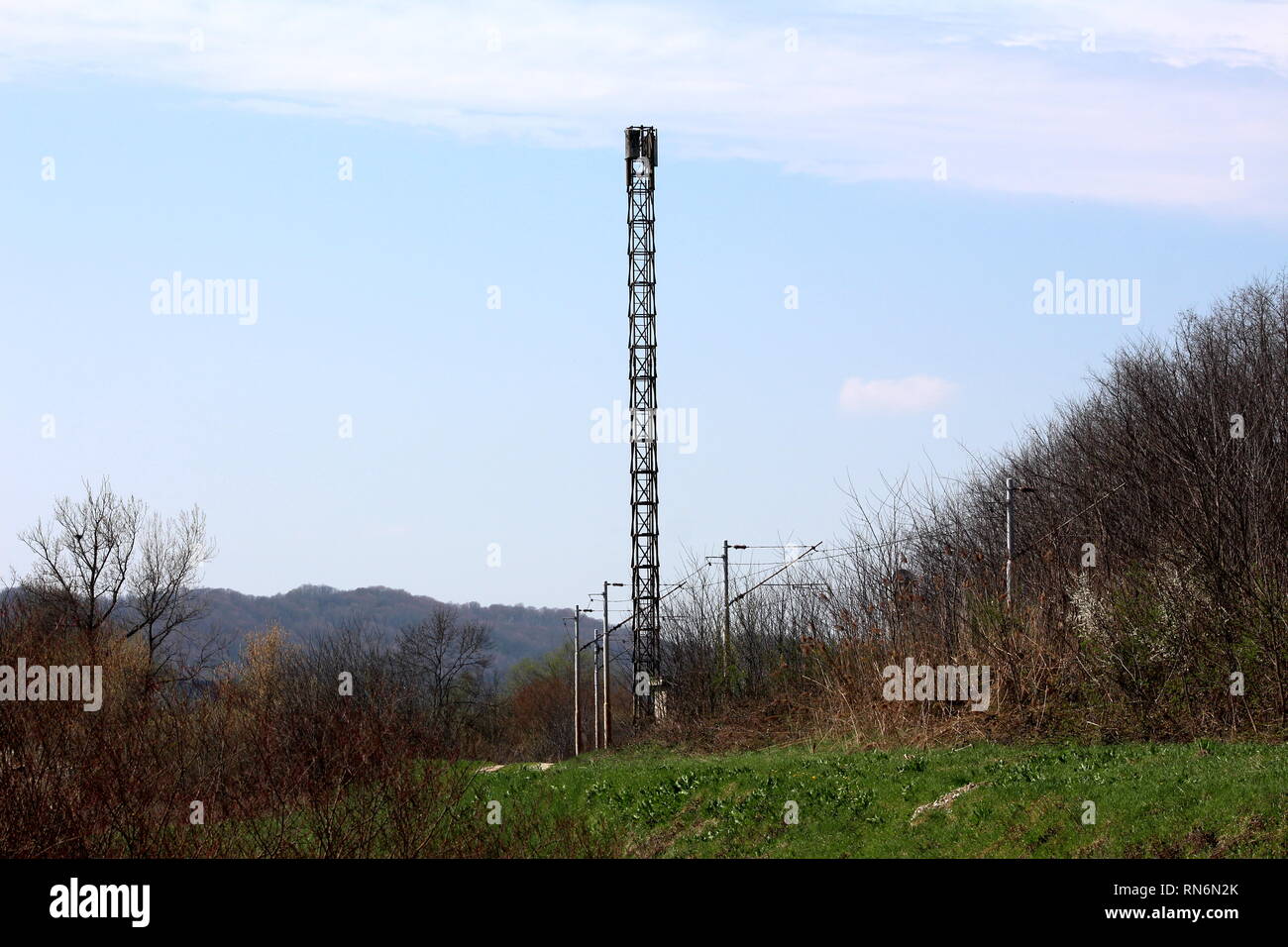 Tall cell phone metal antenna tower next to railroad with multiple ...
