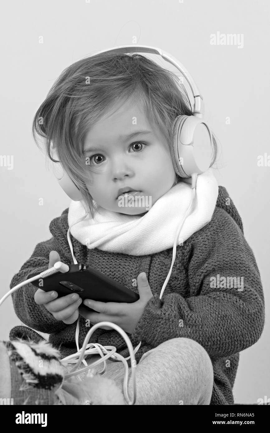 kid listen music with headset and mp3 on phone. having fun. winter kid ...