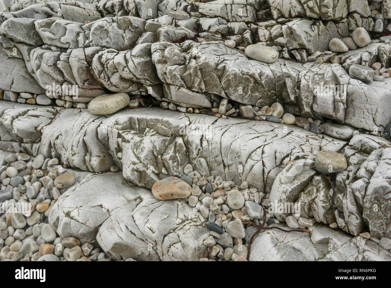 Abstract of white pebbles and dark rock on a Northern Ireland beach ...