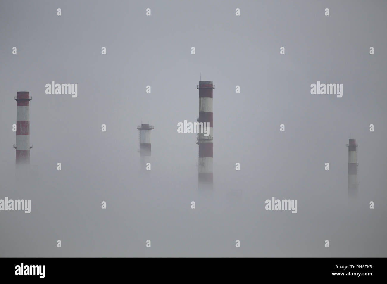 Oil refinery chimneys semi losted in the fog Stock Photo - Alamy