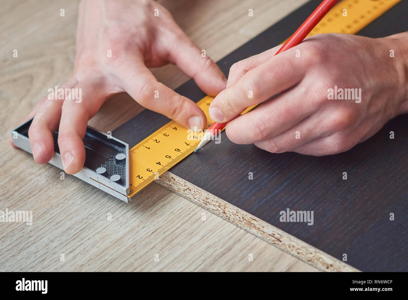 Male hands with ruler and pencil taking measurement of wooden plank ...