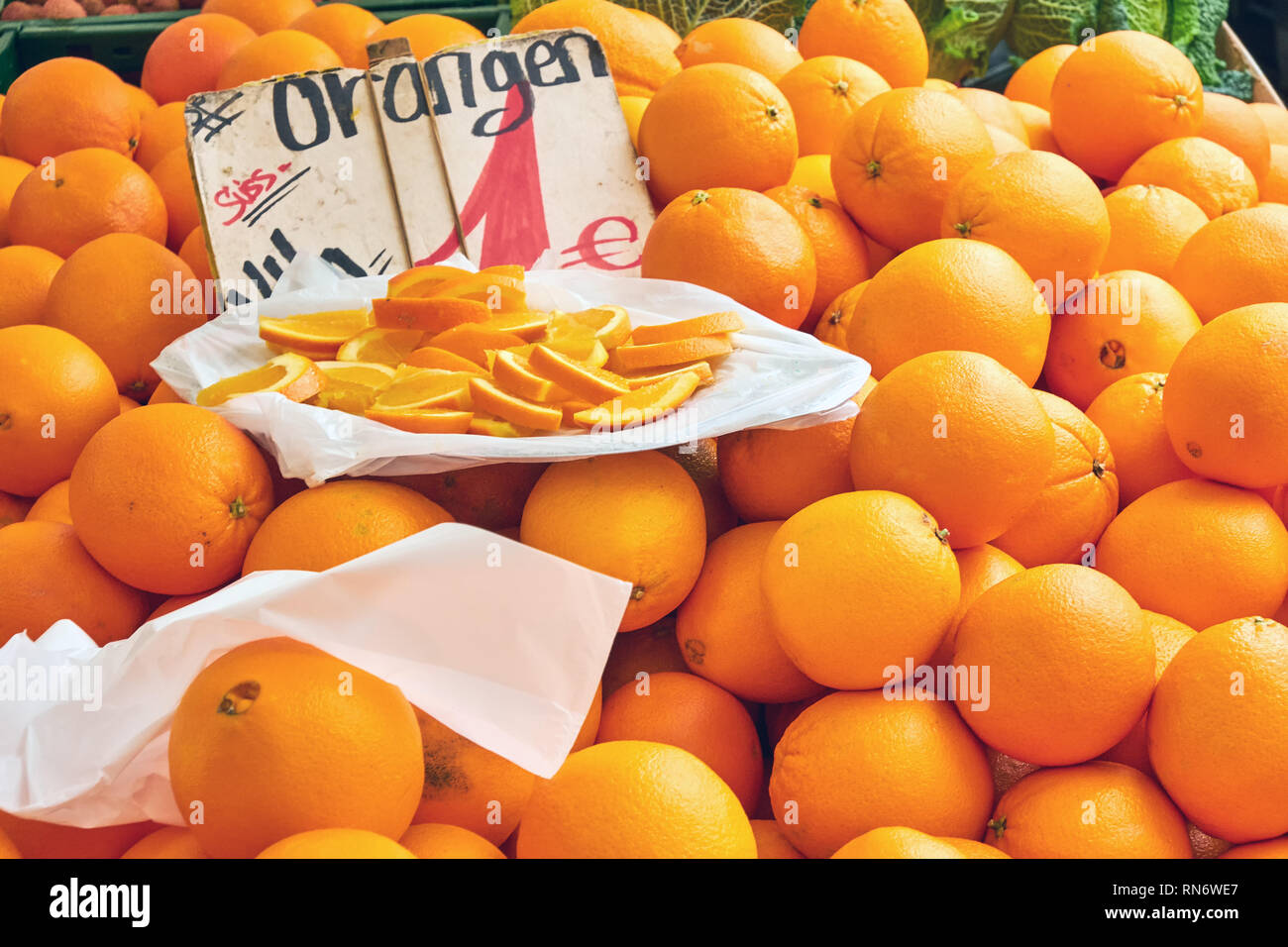 Oranges for sale at a market with some slieces on a plate Stock Photo ...