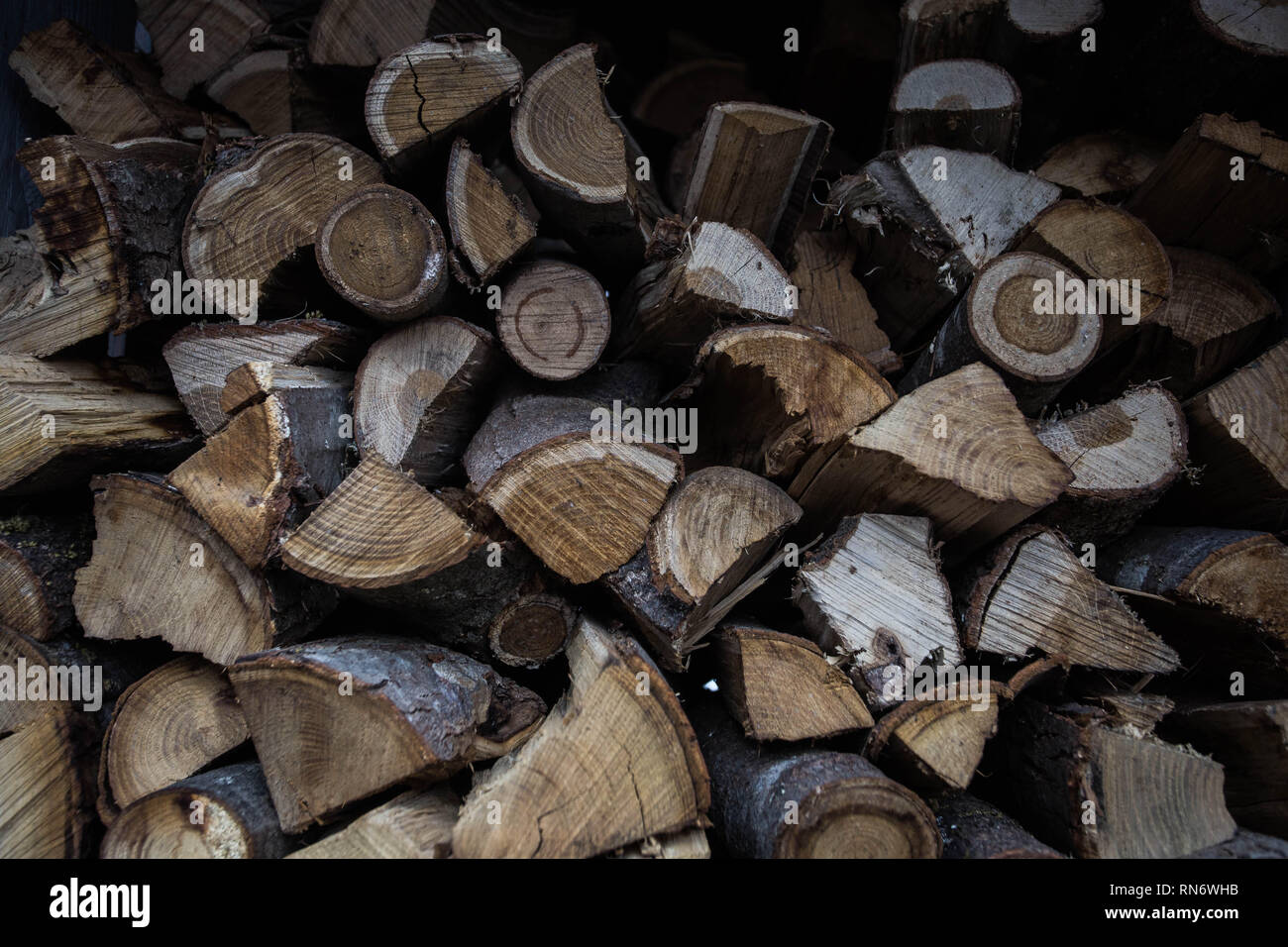 Wall of stacked wood logs as background dark shadows Stock Photo - Alamy