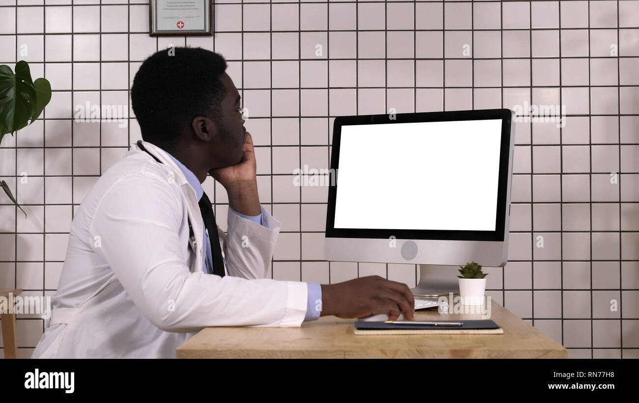 Young african doctor looking on monitor of his computer. White Display ...