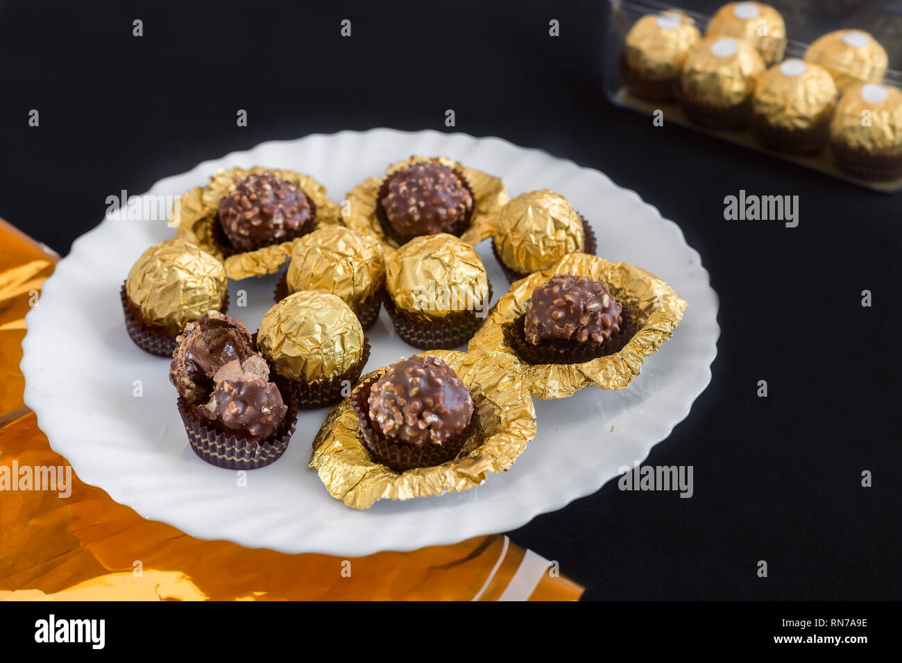 On the table on a white plate chocolates with nuts, wrapped in gold ...