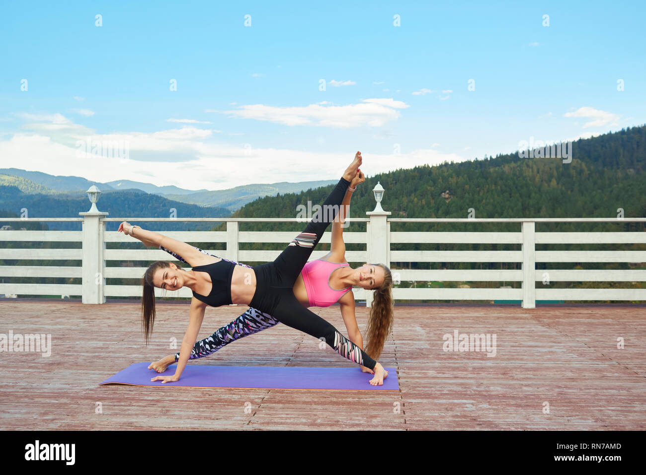 Sportive and flexible women stretching, balancing on yoga mat. Two ...