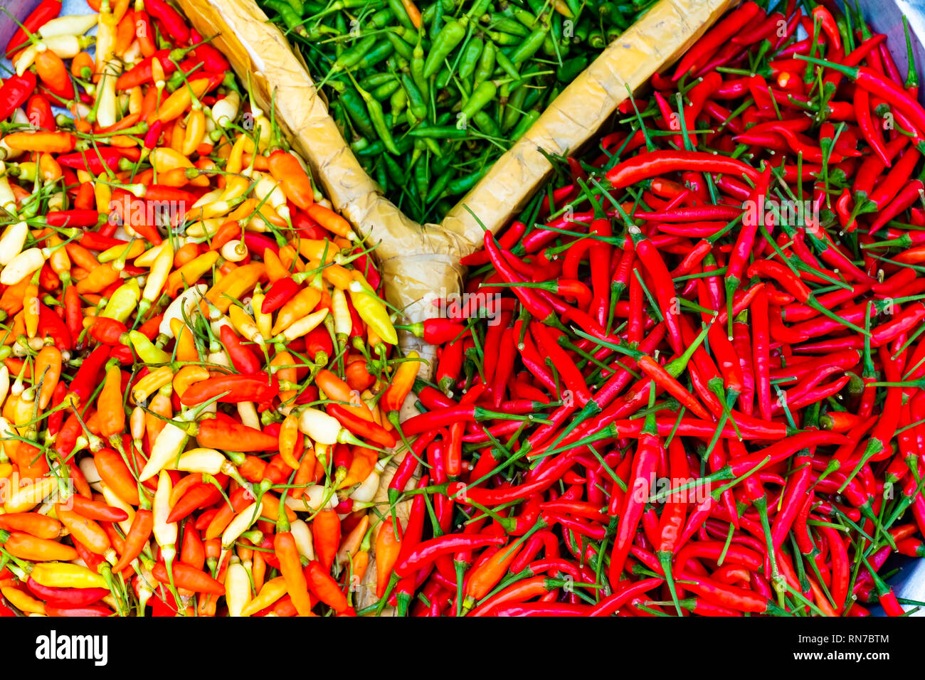 Red, orange, and green chilli on the basket in traditional market of ...