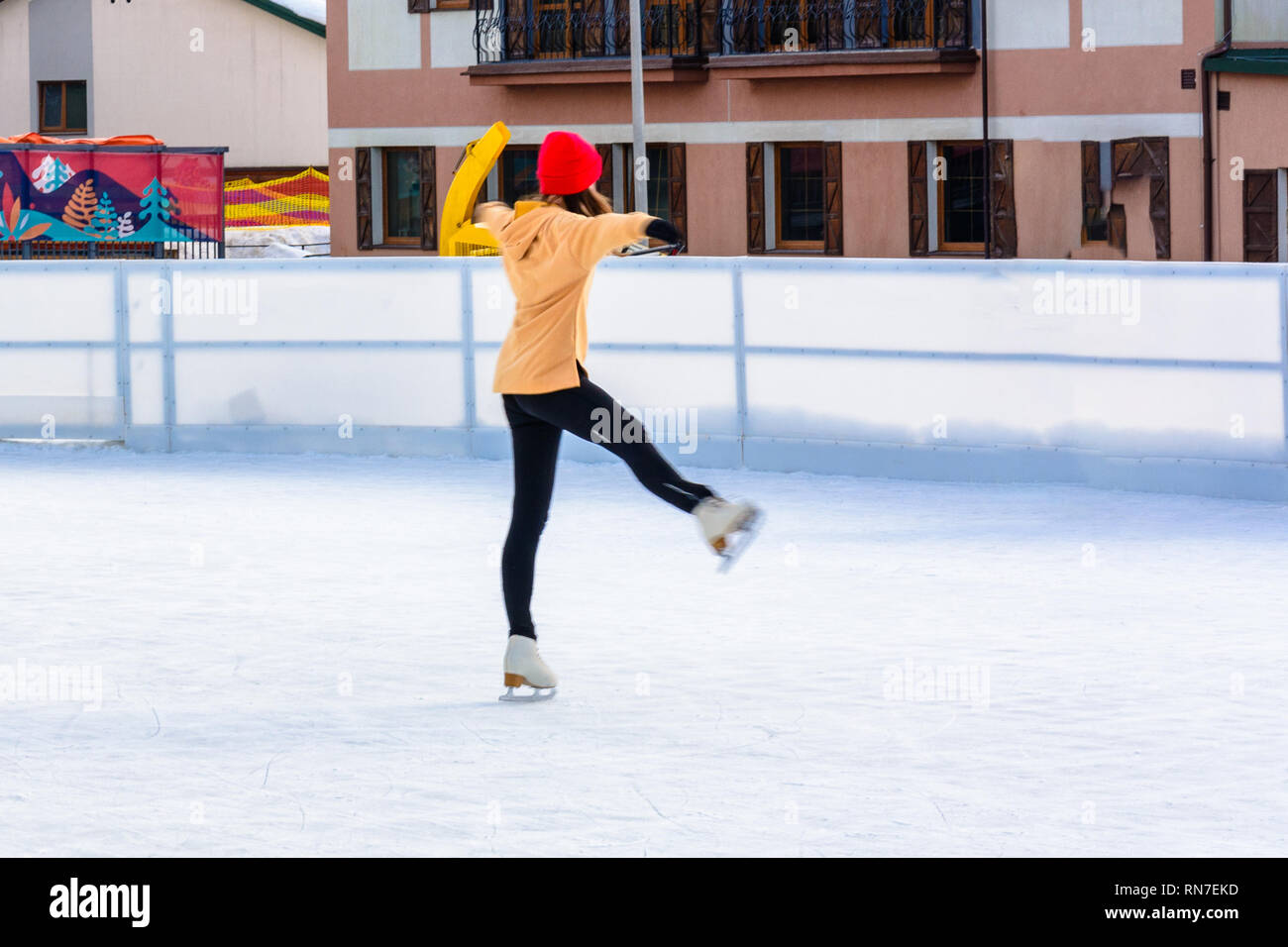 A young, slim girl in outdoor figure skating on a roller skating rink ...