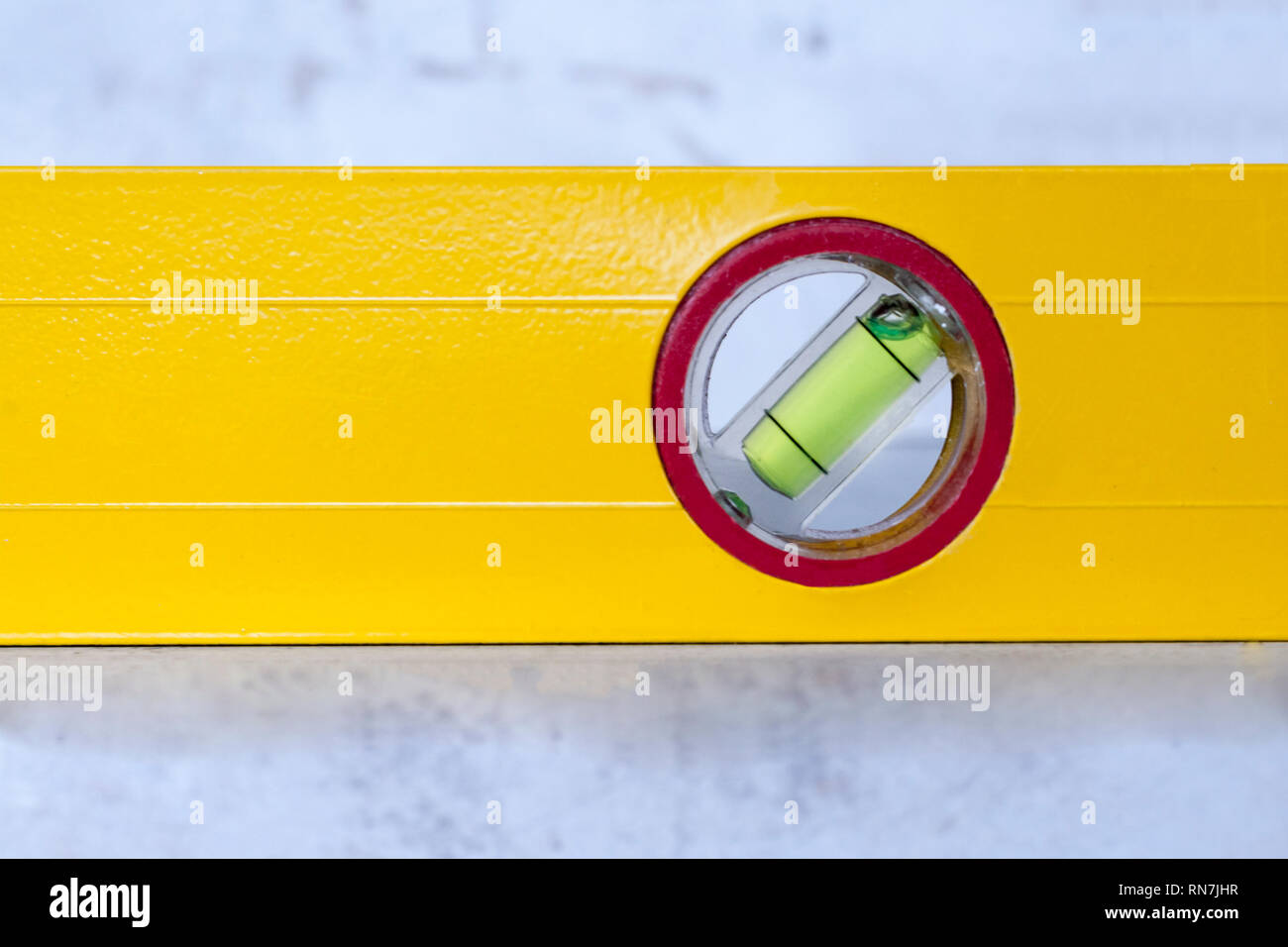 Construction tools a bright yellow level on a light concrete background ...