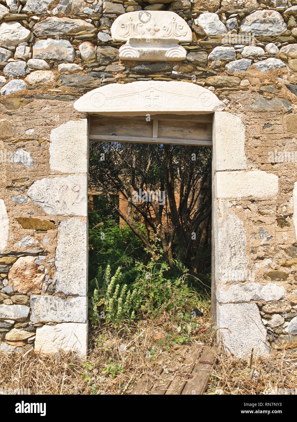 Building detail of fallen door on stone wall in Mani Greece with sybols ...