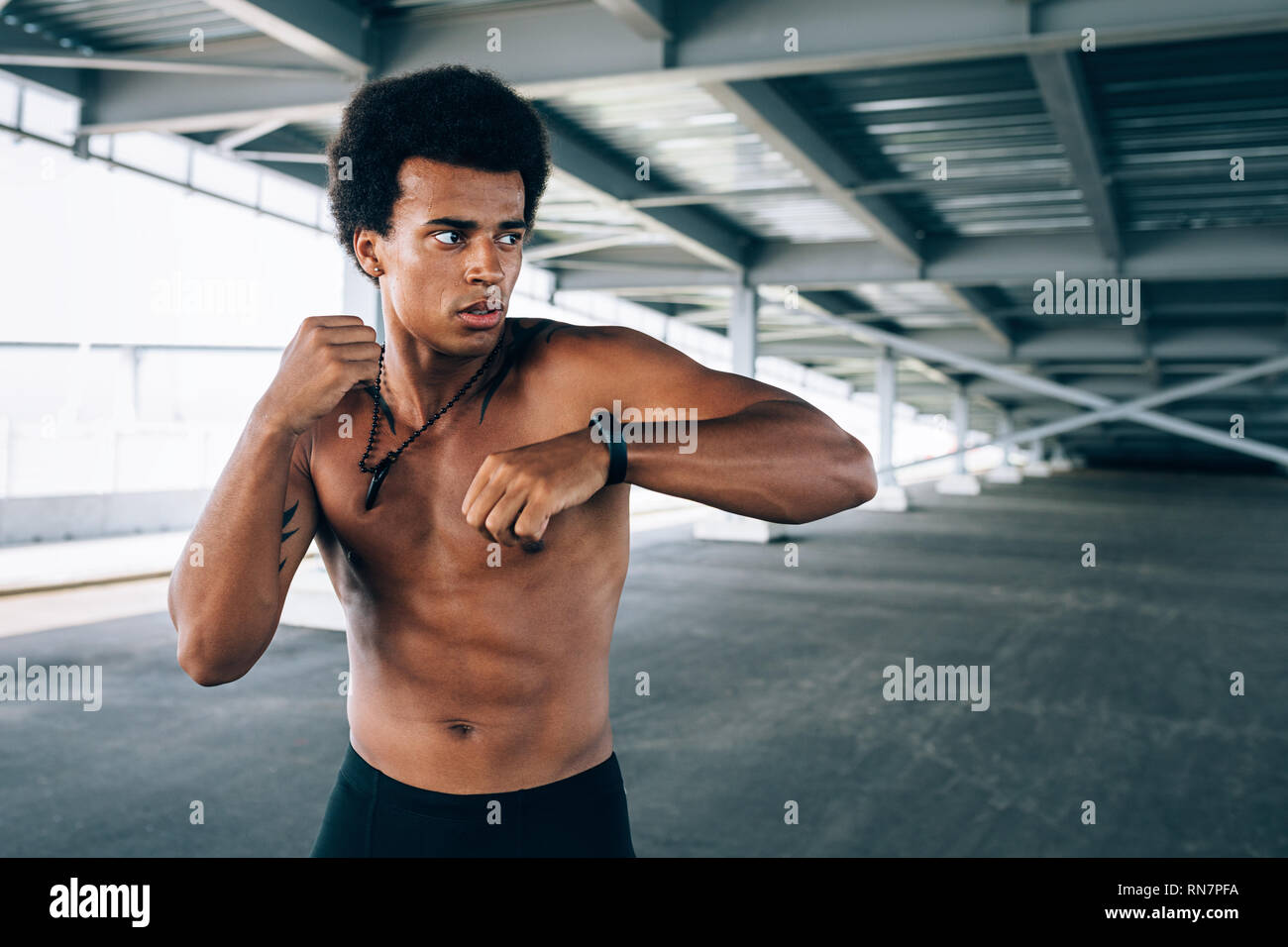 Bare-chested kickboxer practicing punches on city street Stock Photo ...