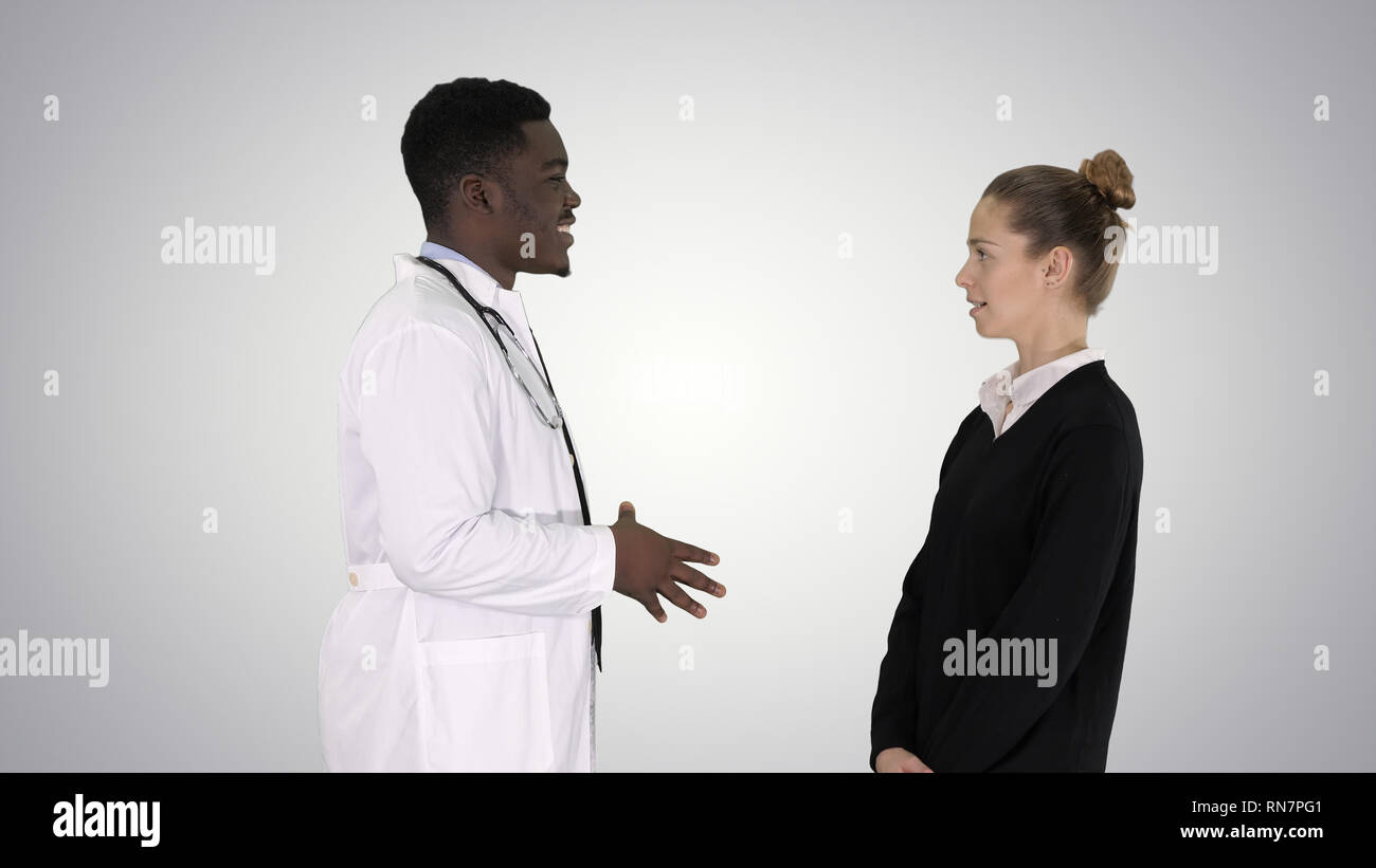 Male african doctor talking to female patient on gradient background ...