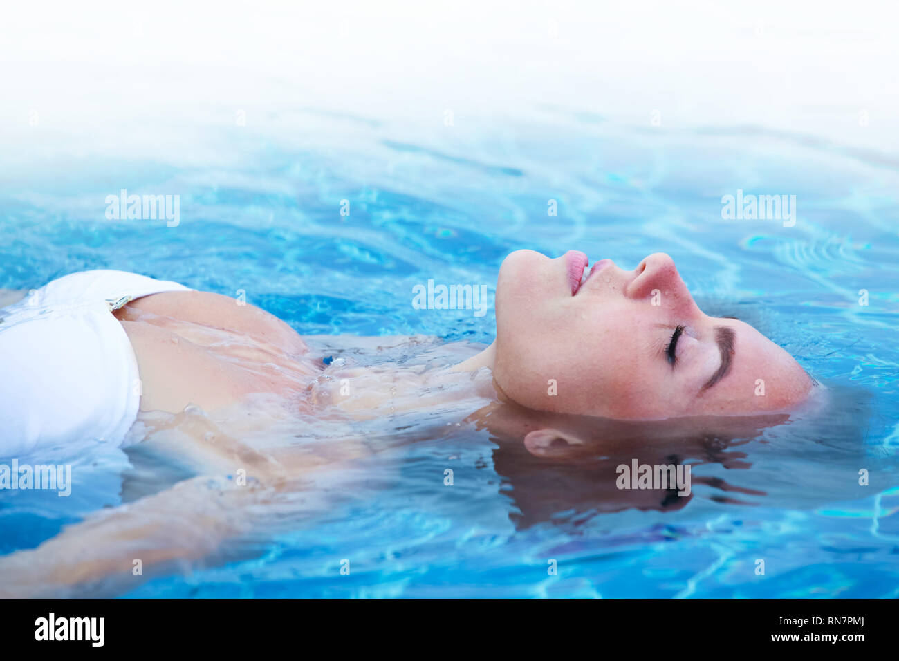 Girl in bikini relaxing floating in blue water of swimming pool Stock ...