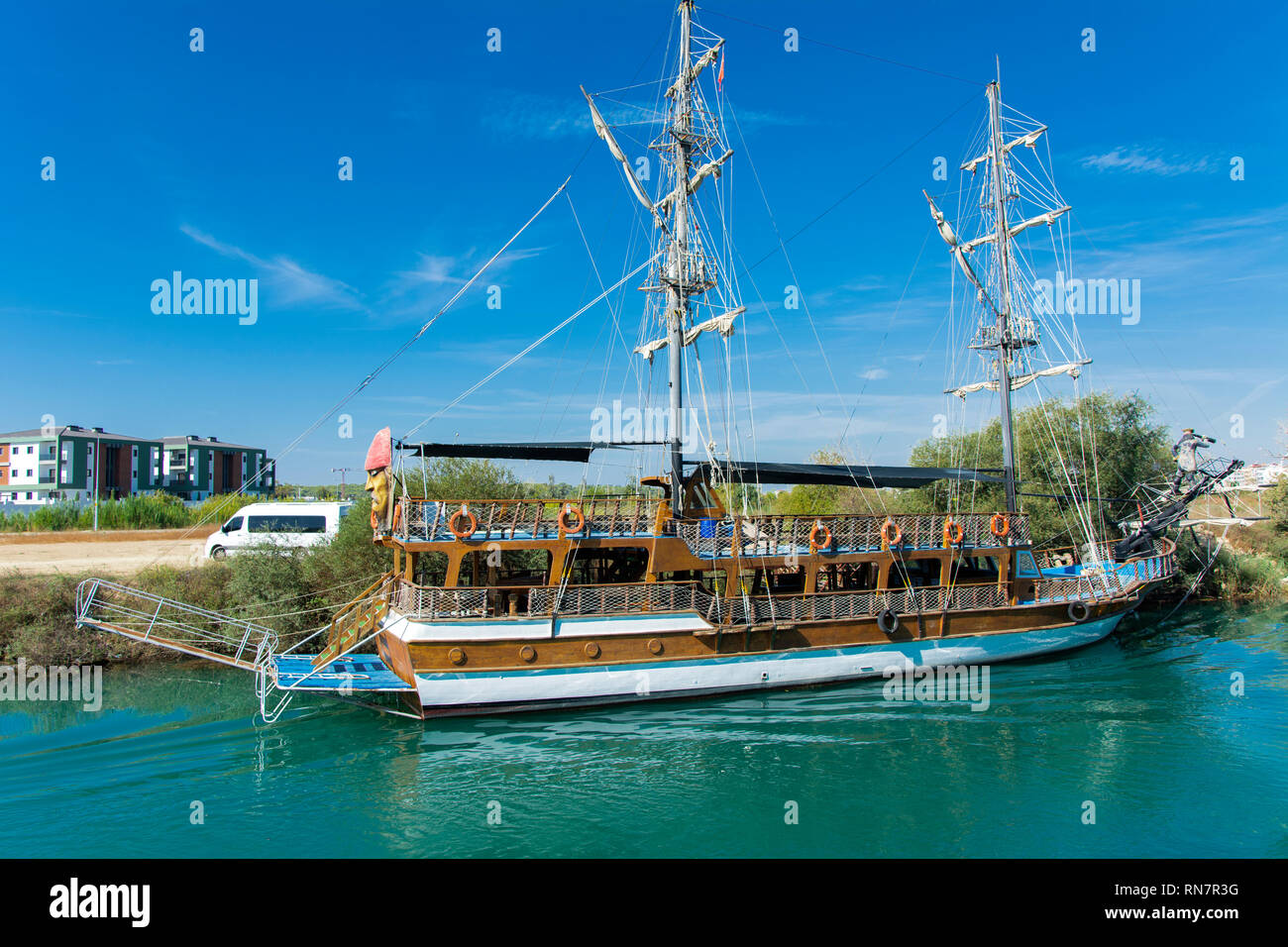 A small sailing ship with tourists passes along the coast against the ...