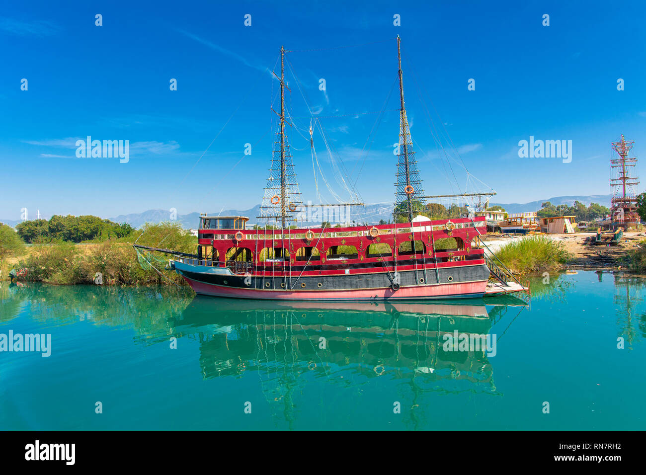 A small sailing ship with tourists passes along the coast against the ...