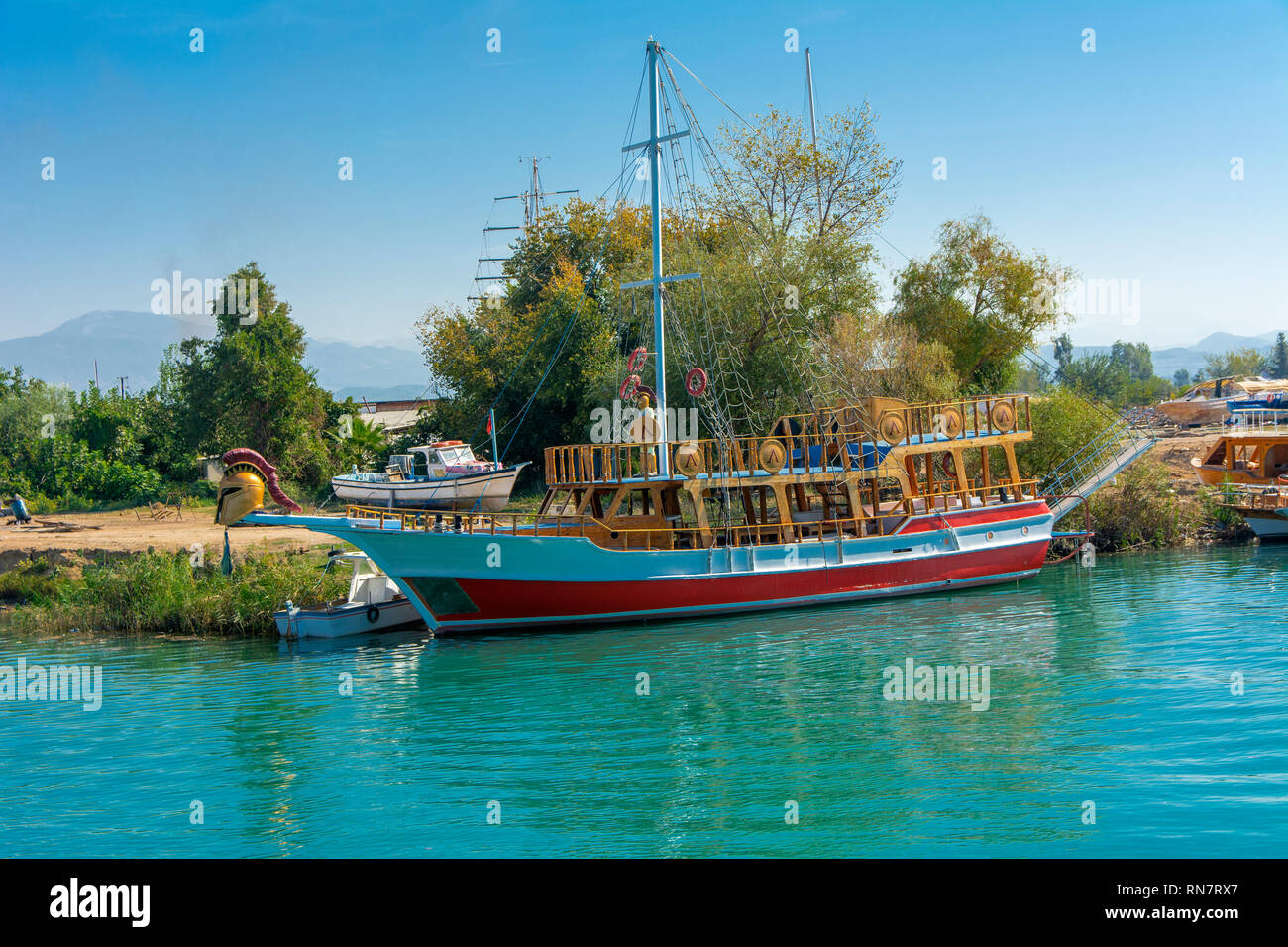 A small sailing ship with tourists passes along the coast against the ...