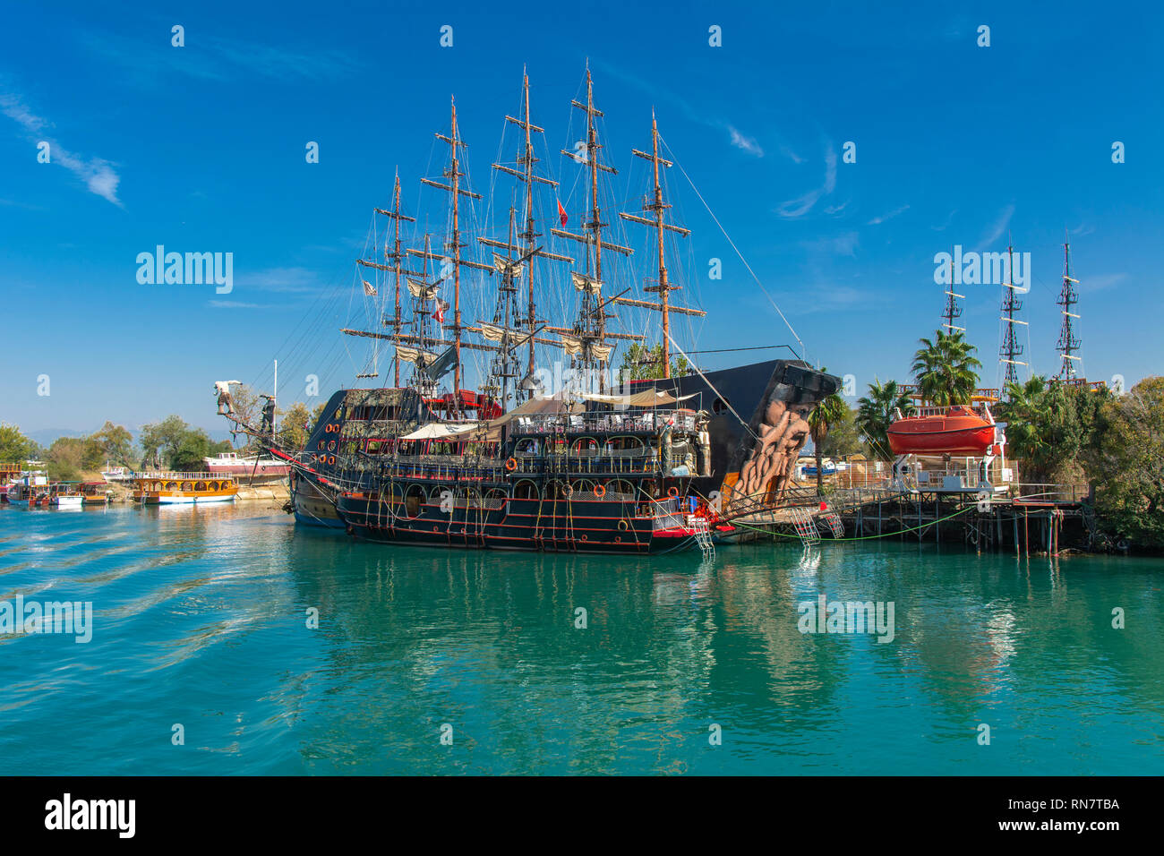 A small sailing ship with tourists passes along the coast against the ...