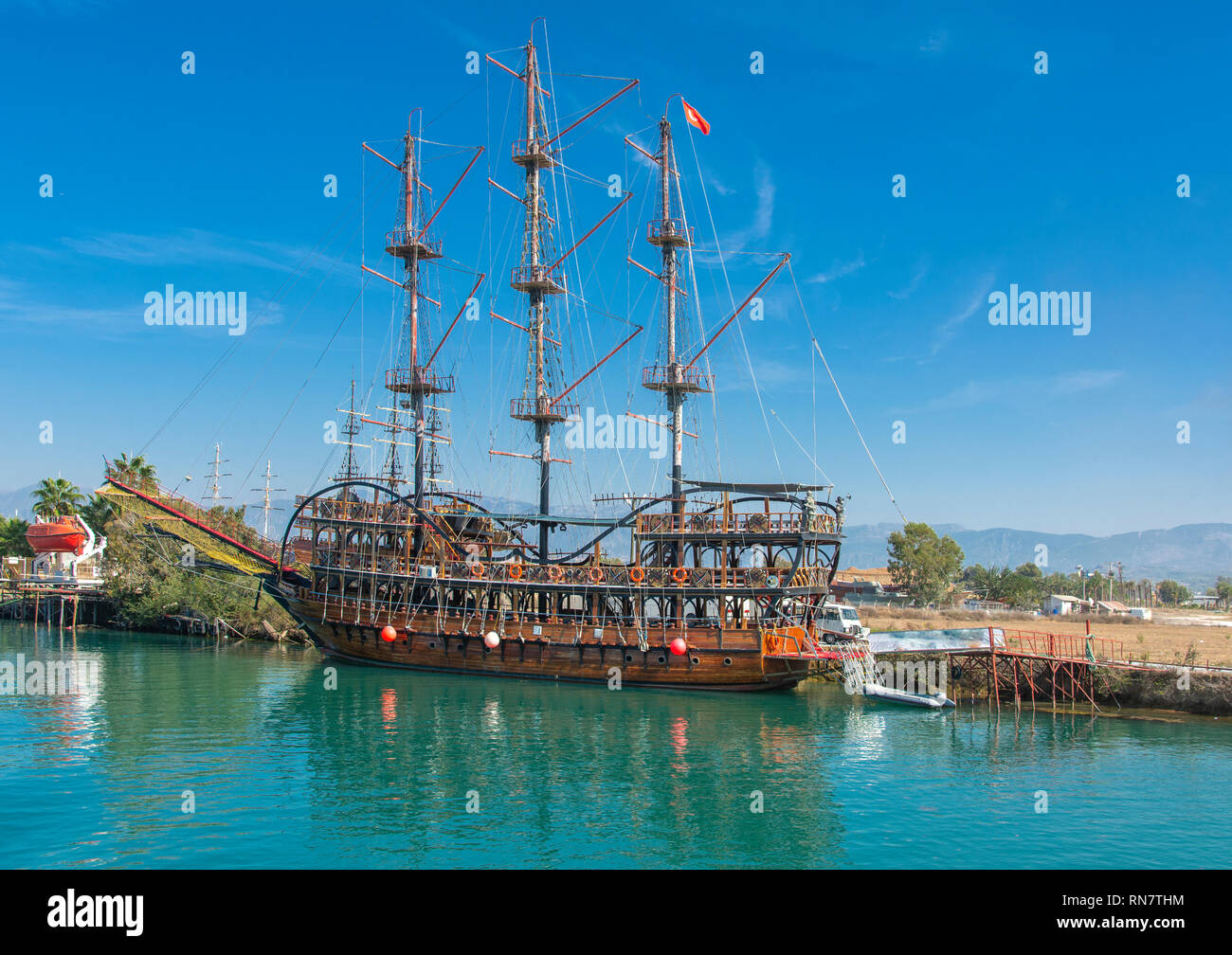 A small sailing ship with tourists passes along the coast against the ...