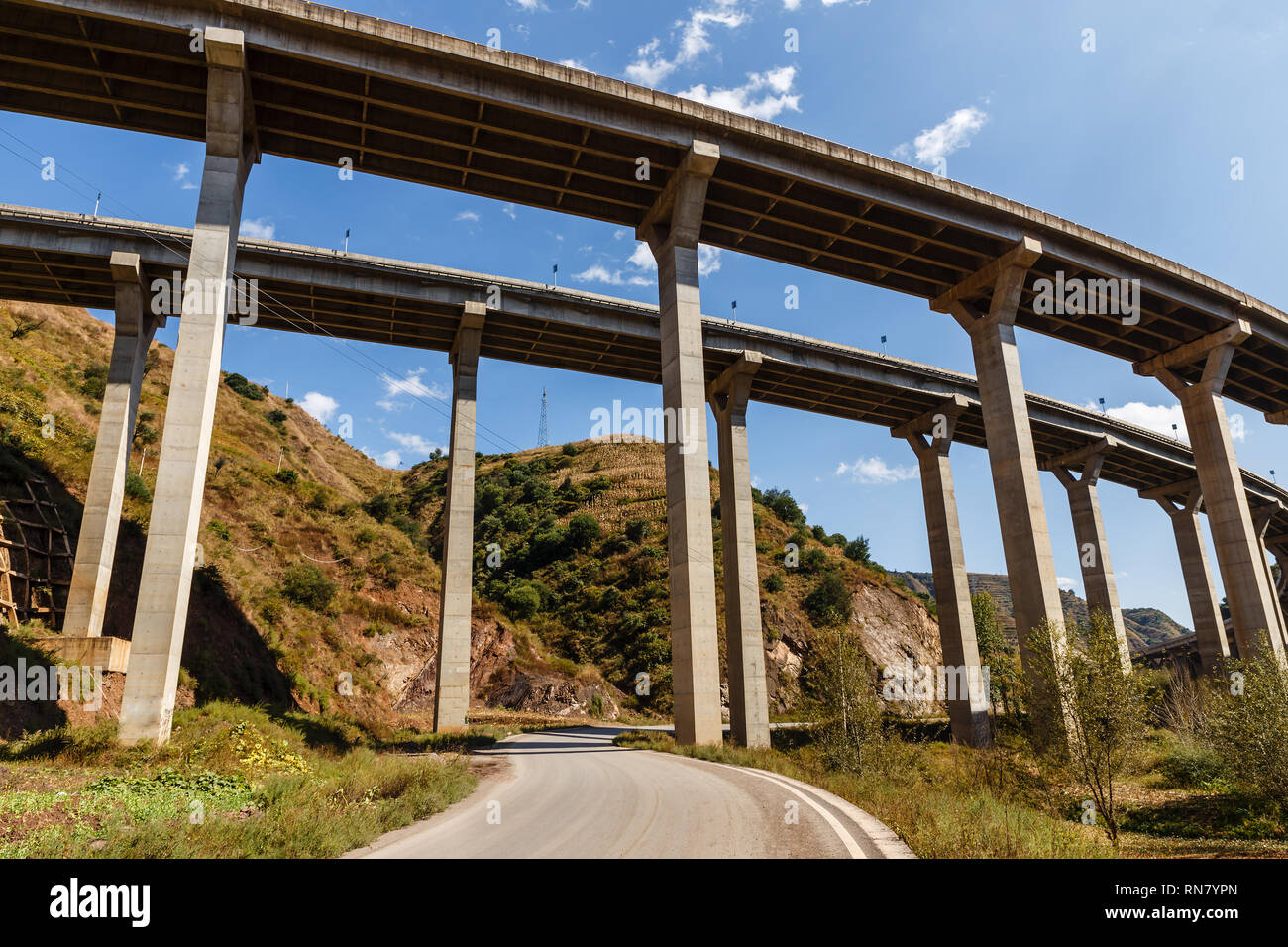 asphalt road in the mountains passes under a highway overpass bridge ...
