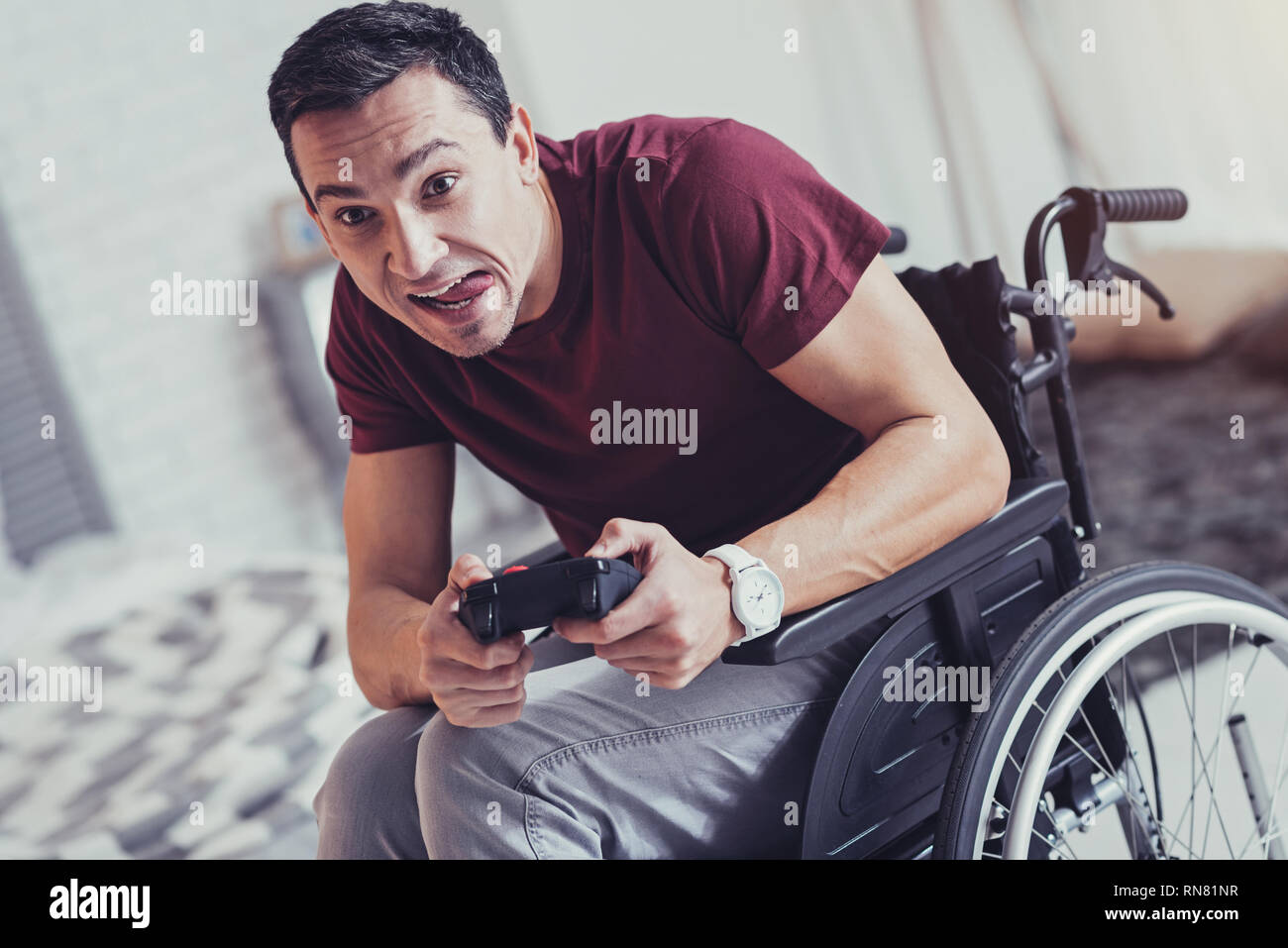 Compulsive gamer. Nice paralyzed man holding a game console while being ...
