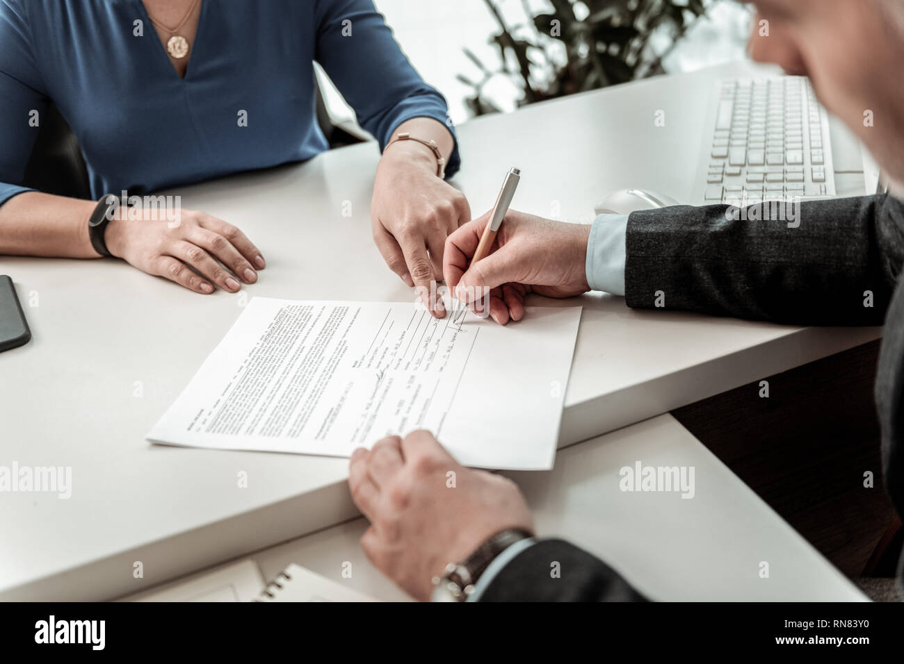 Woman with a watch on her hand showing the place for signature to the ...