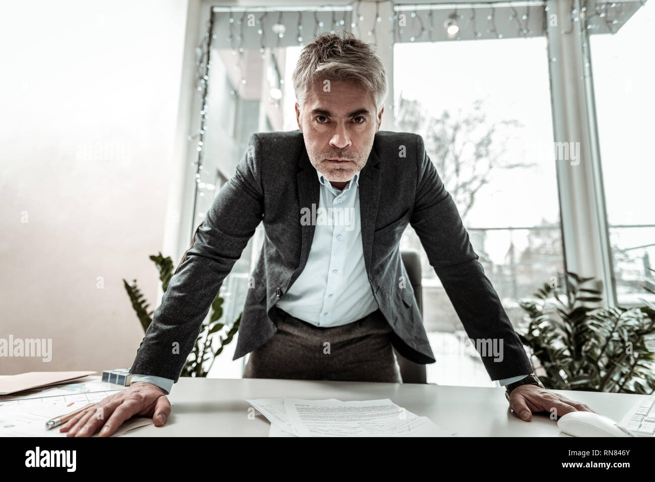 Tall grey-haired adult manager in eyeglasses looking irritated Stock ...