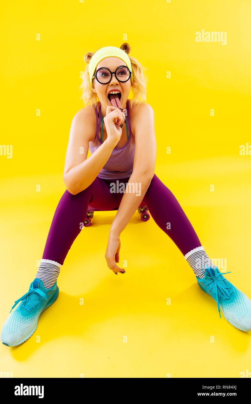 Funny woman eating sweet candy after riding skateboard Stock Photo - Alamy