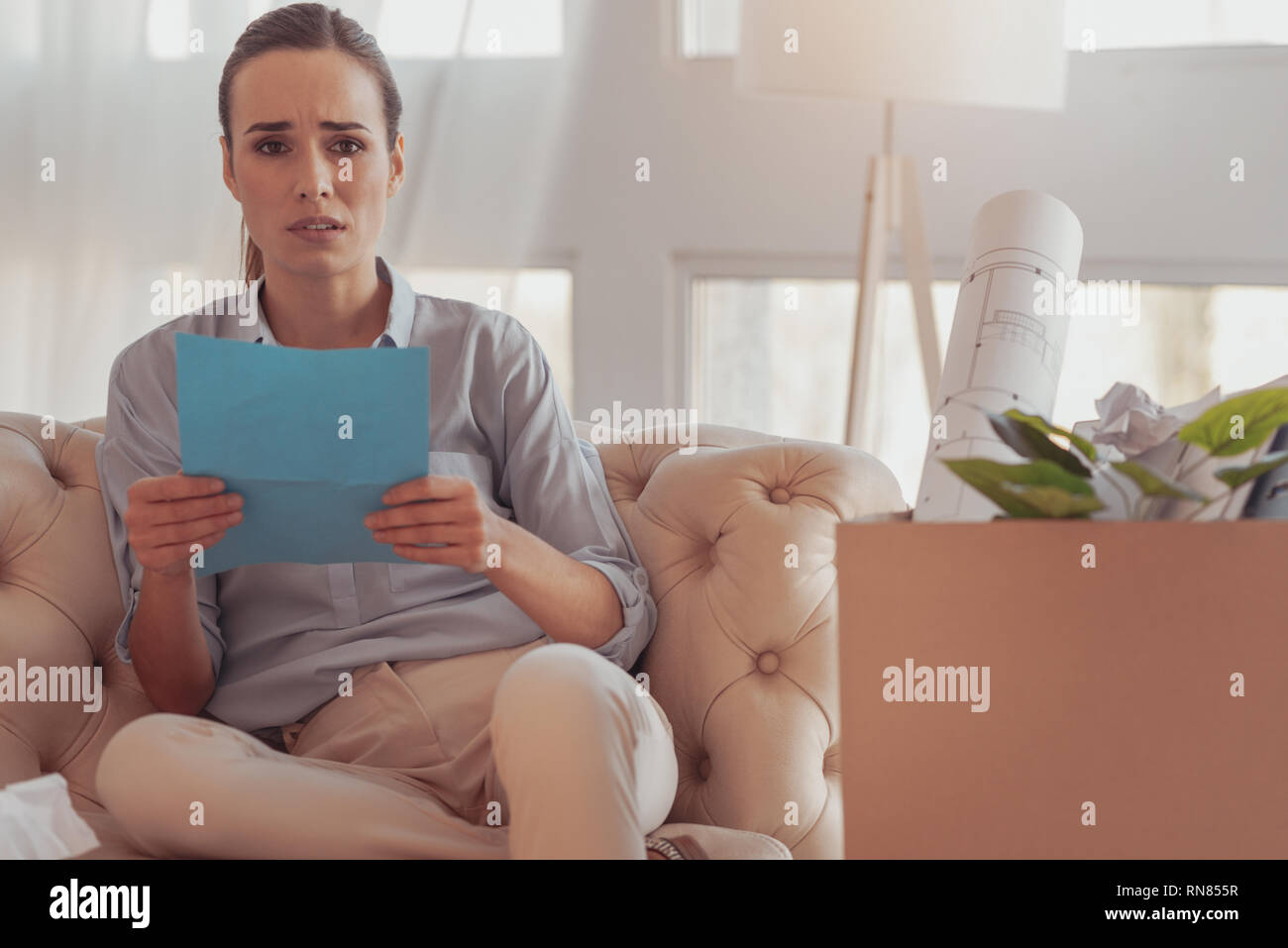 Sadness. Unemployed young woman expressing sorrow while sitting on the ...