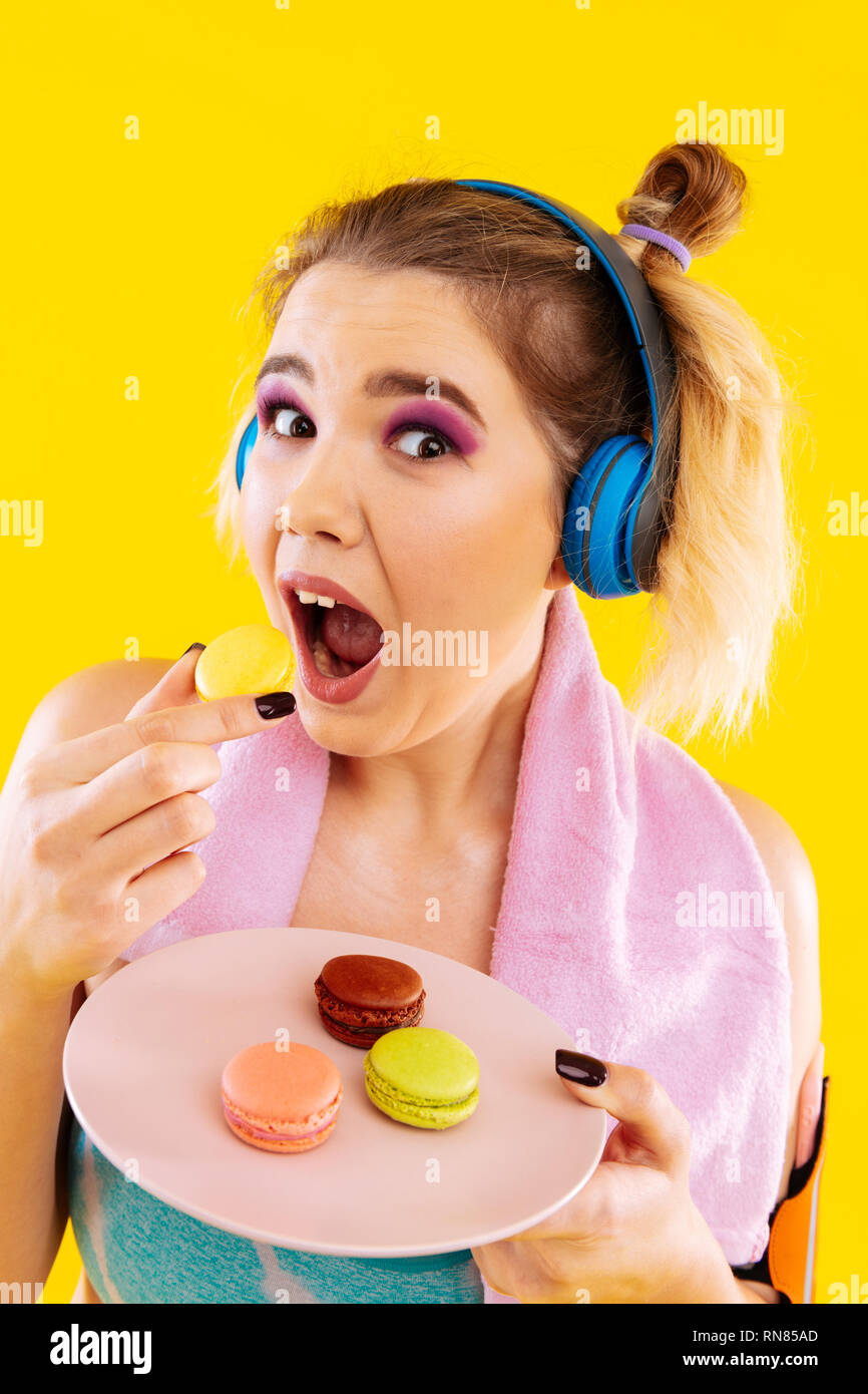 Woman not controlling herself after gym while eating macaron Stock ...