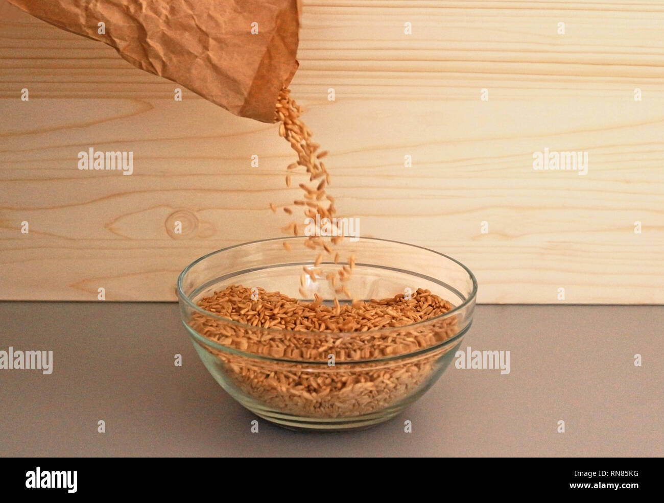 pouring oats from a brown paper bag into a glass bowl in a kitchen with ...