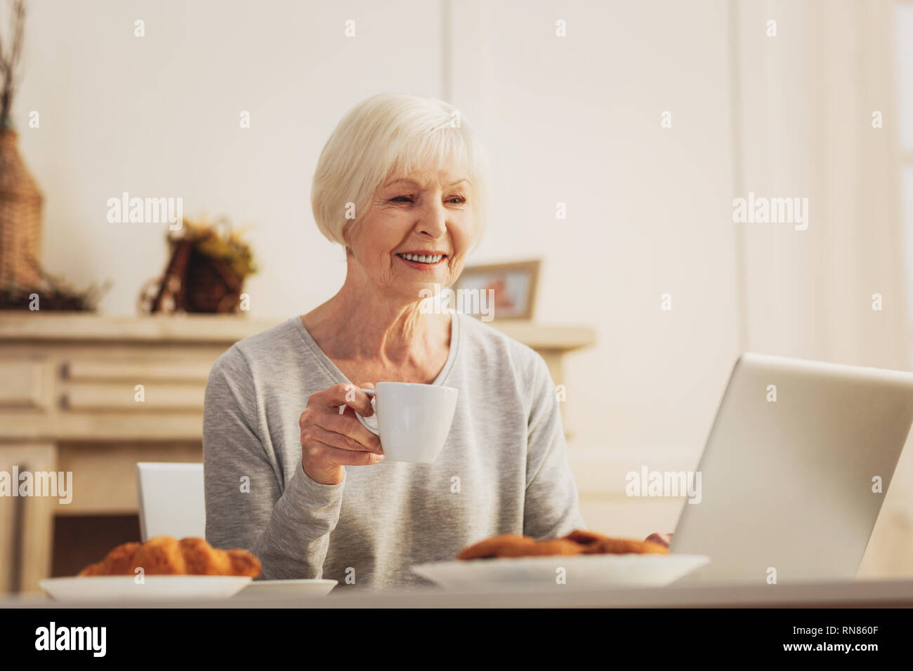 Warm pastry. Pleasant woman eating delicious warm pastry while watching ...