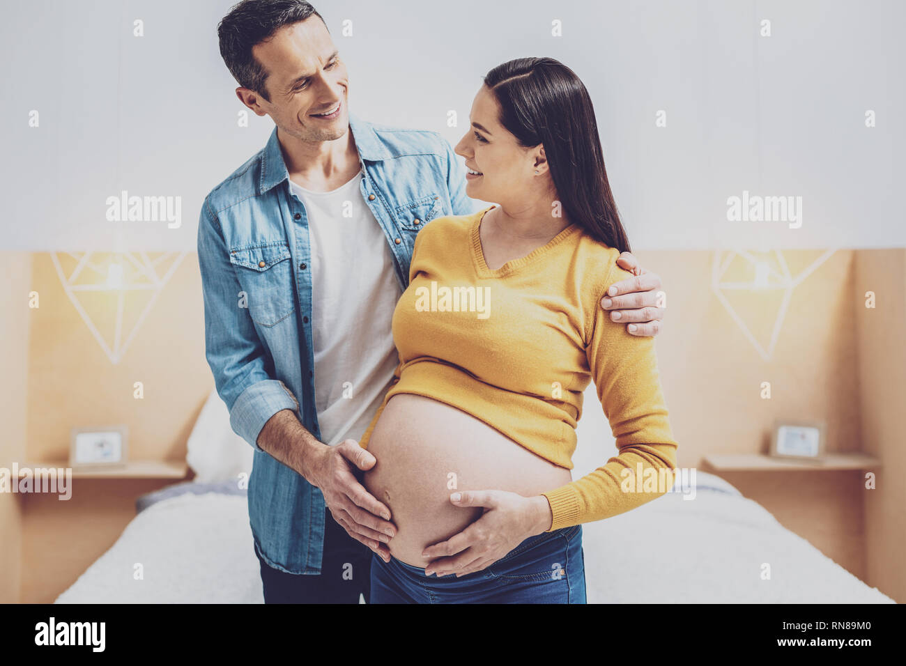 So happy. Charming brunette female keeping smile on face and turning head to her man Stock Photo ...