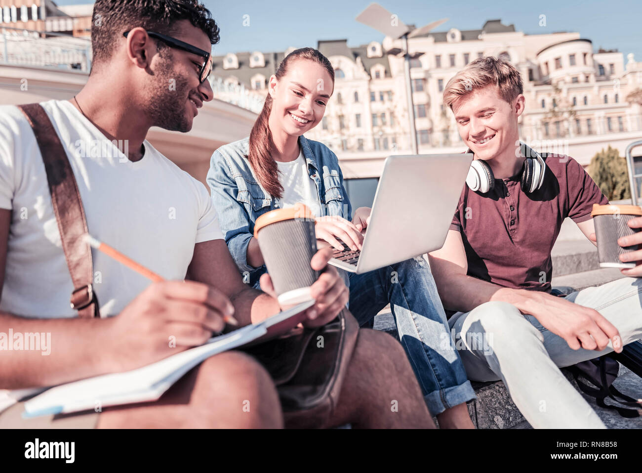 Group mates. Delighted friends sitting outside and drinking coffee ...
