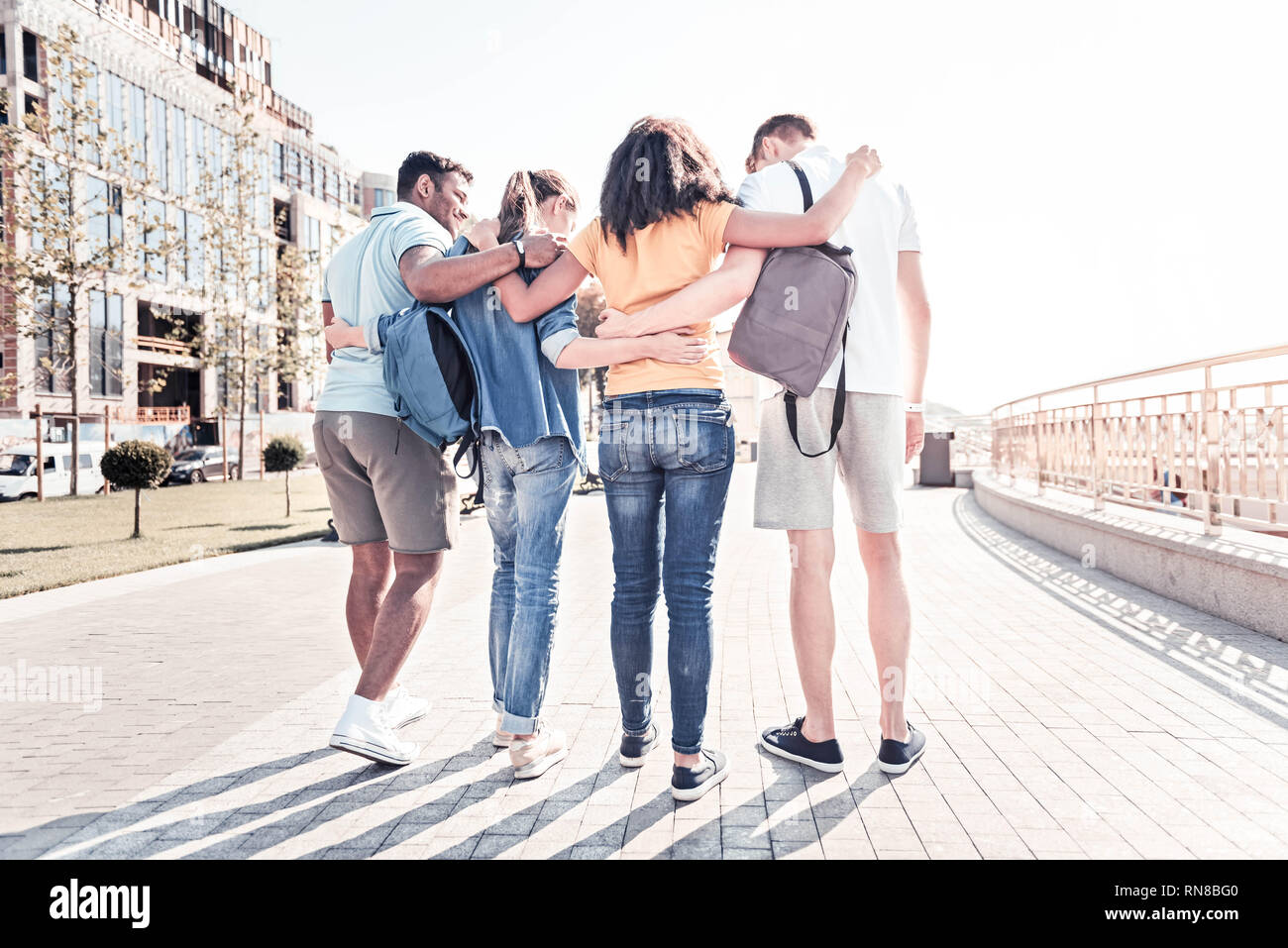 Good support. Joyful young people embracing each other and standing ...