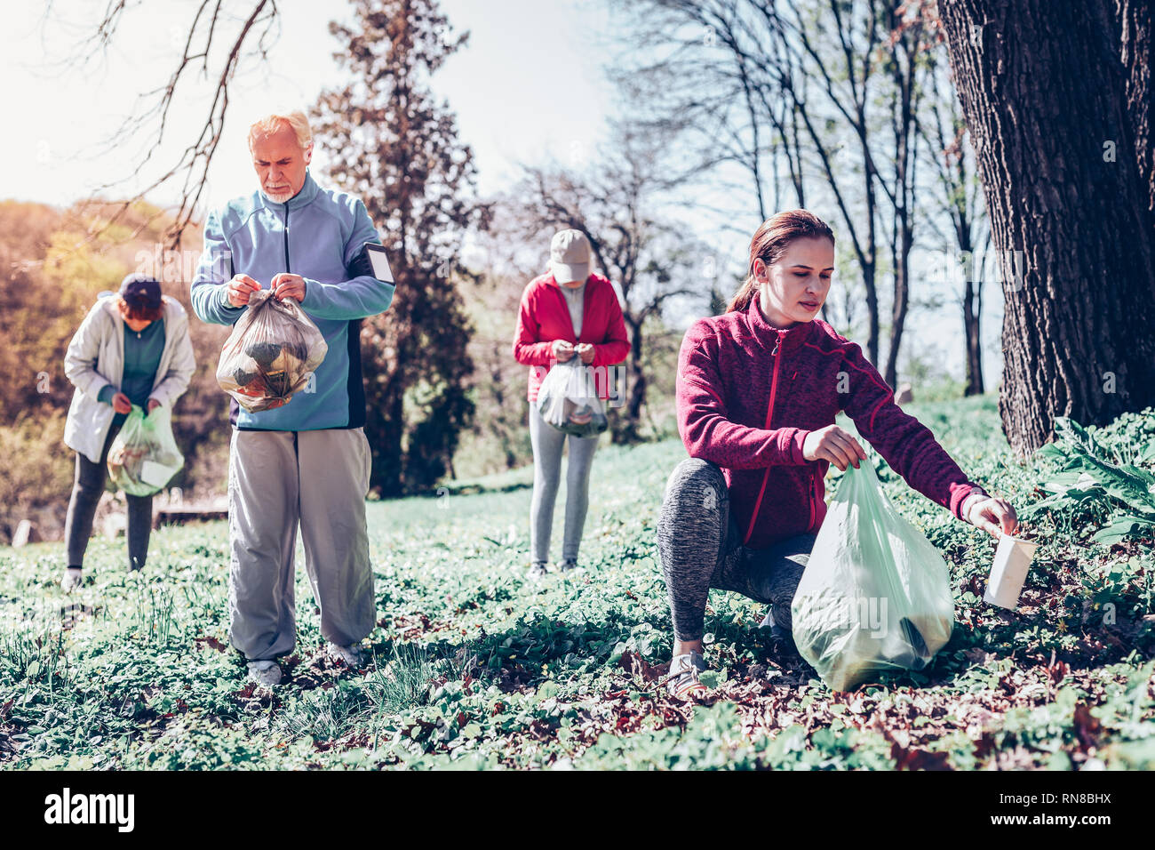Gathering garbage. Four socially active people feeling responsible ...