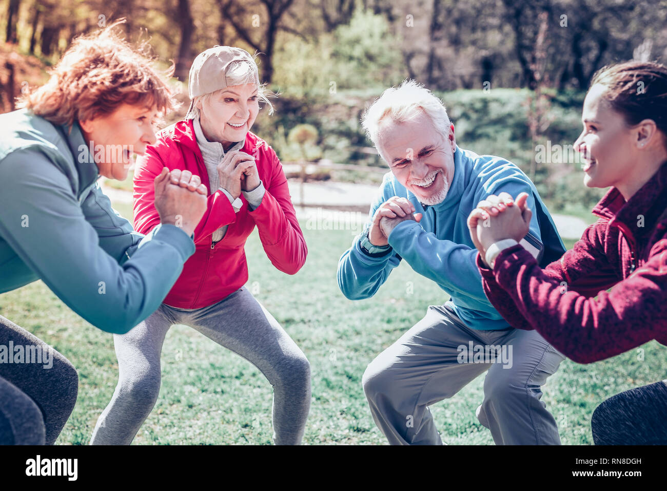 Morning exercises. Group of active retired people looking at couch and ...