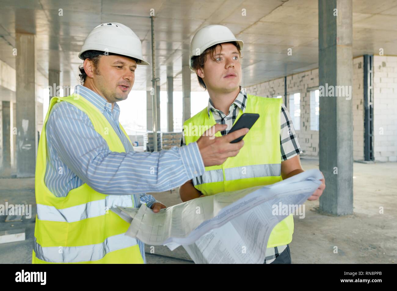 Male construction worker and engineer at the construction site ...