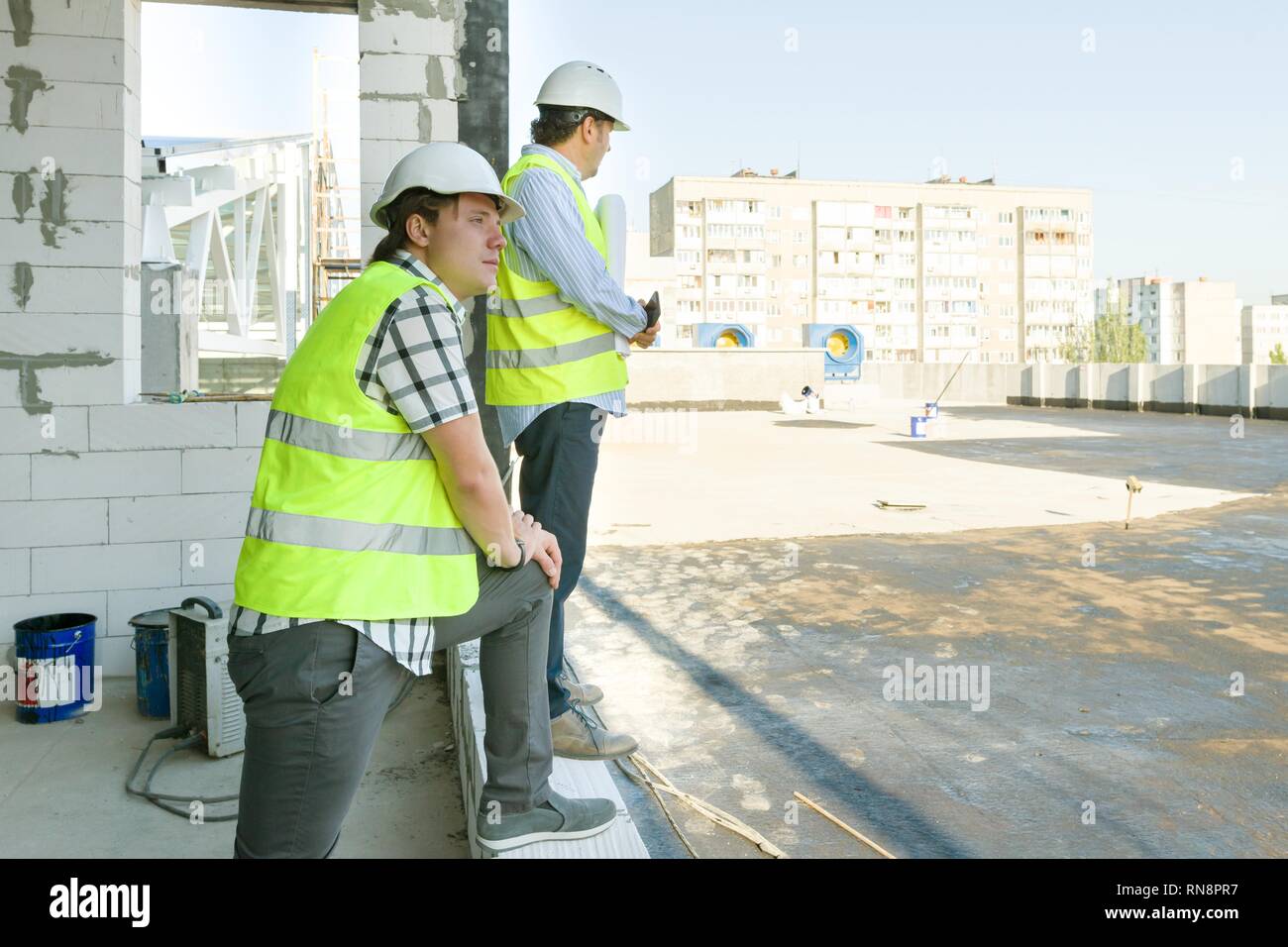 Male builders on the roof of construction site. Building, development ...