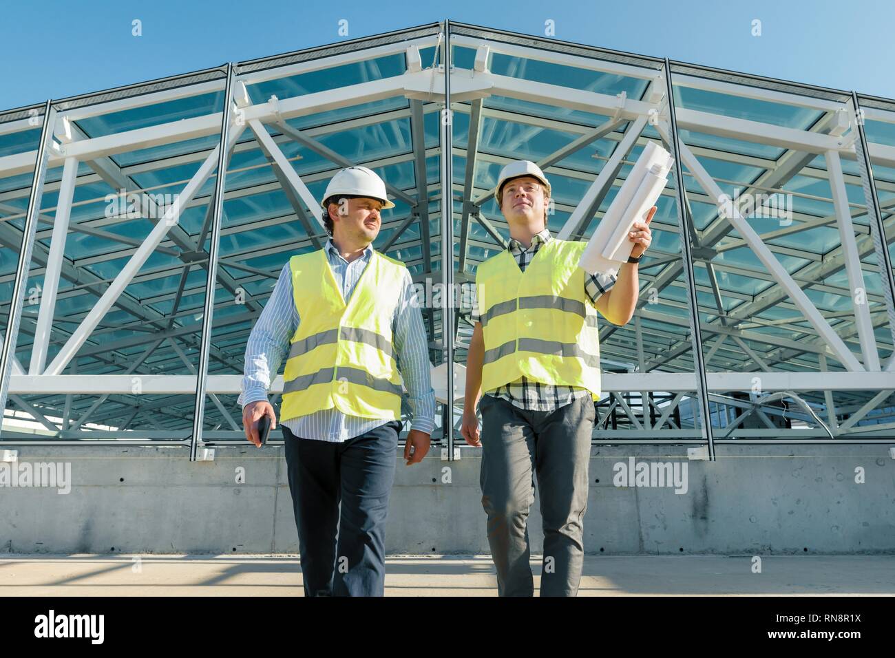 Male builders go forward on roof of construction site. Building ...
