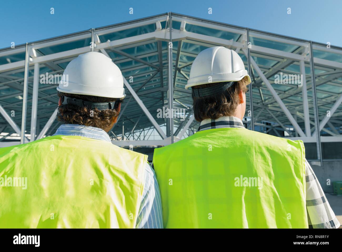 Male builders on roof of construction site,back view. Building ...