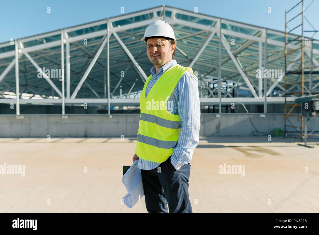 Portrait of male engineer at construction site, builder with blueprint ...