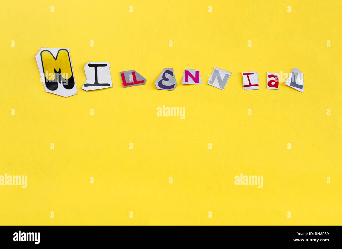 Word Millennial formed with cut out letters on yellow background ...