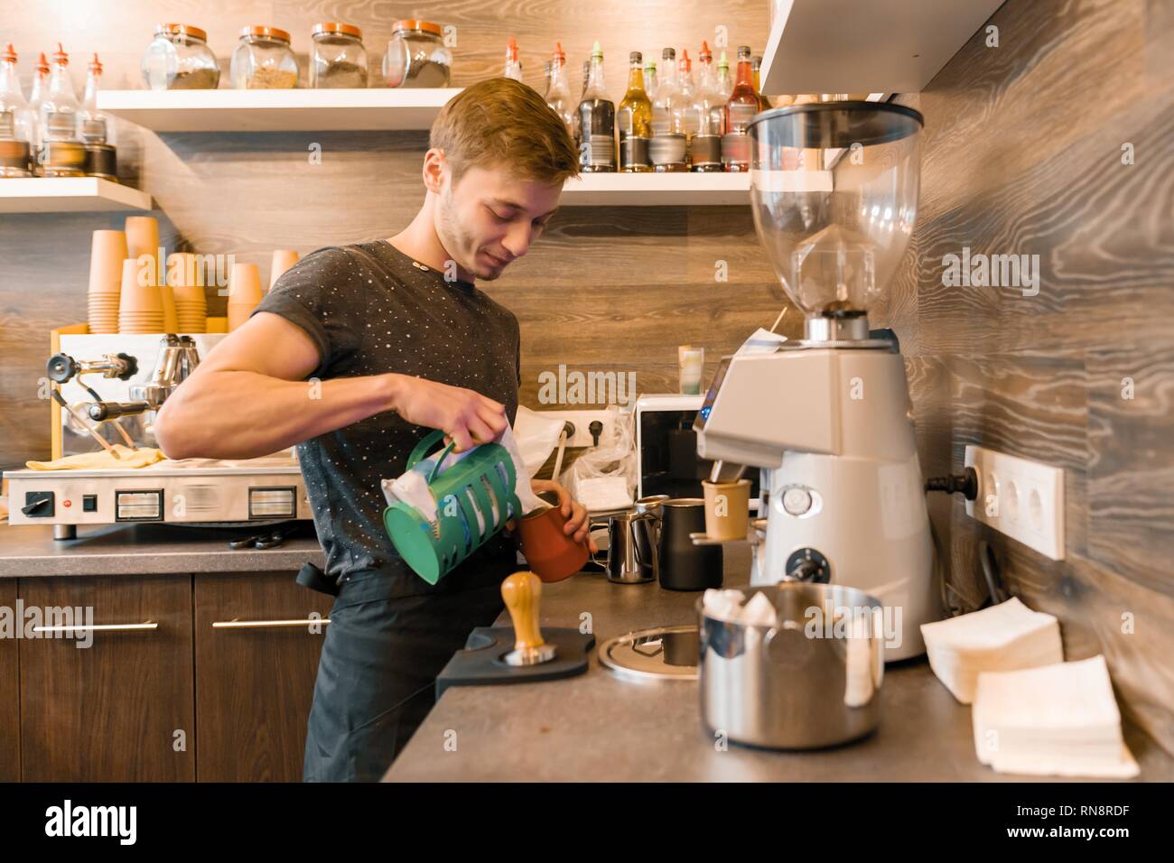 Young male coffee shop worker making coffee with machine Stock Photo ...