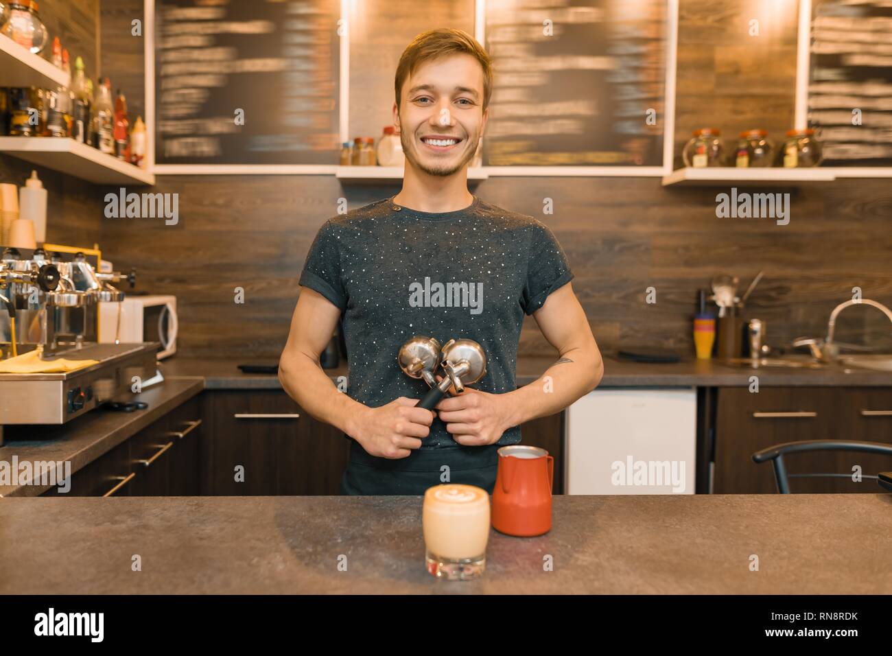 Portrait of young smiling male cafe worker, standing at the counter ...