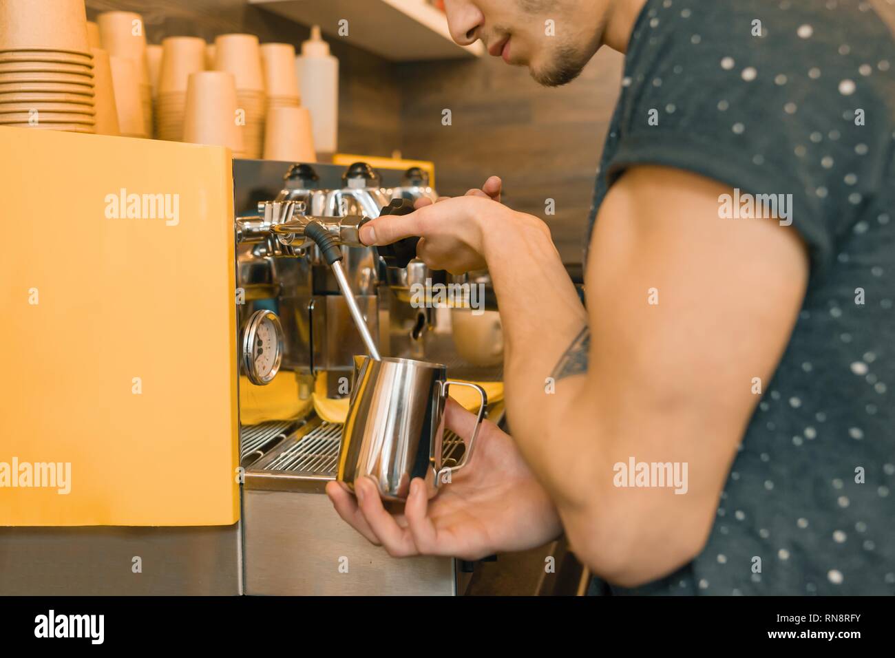 Young male coffee shop worker making coffee with machine Stock Photo ...