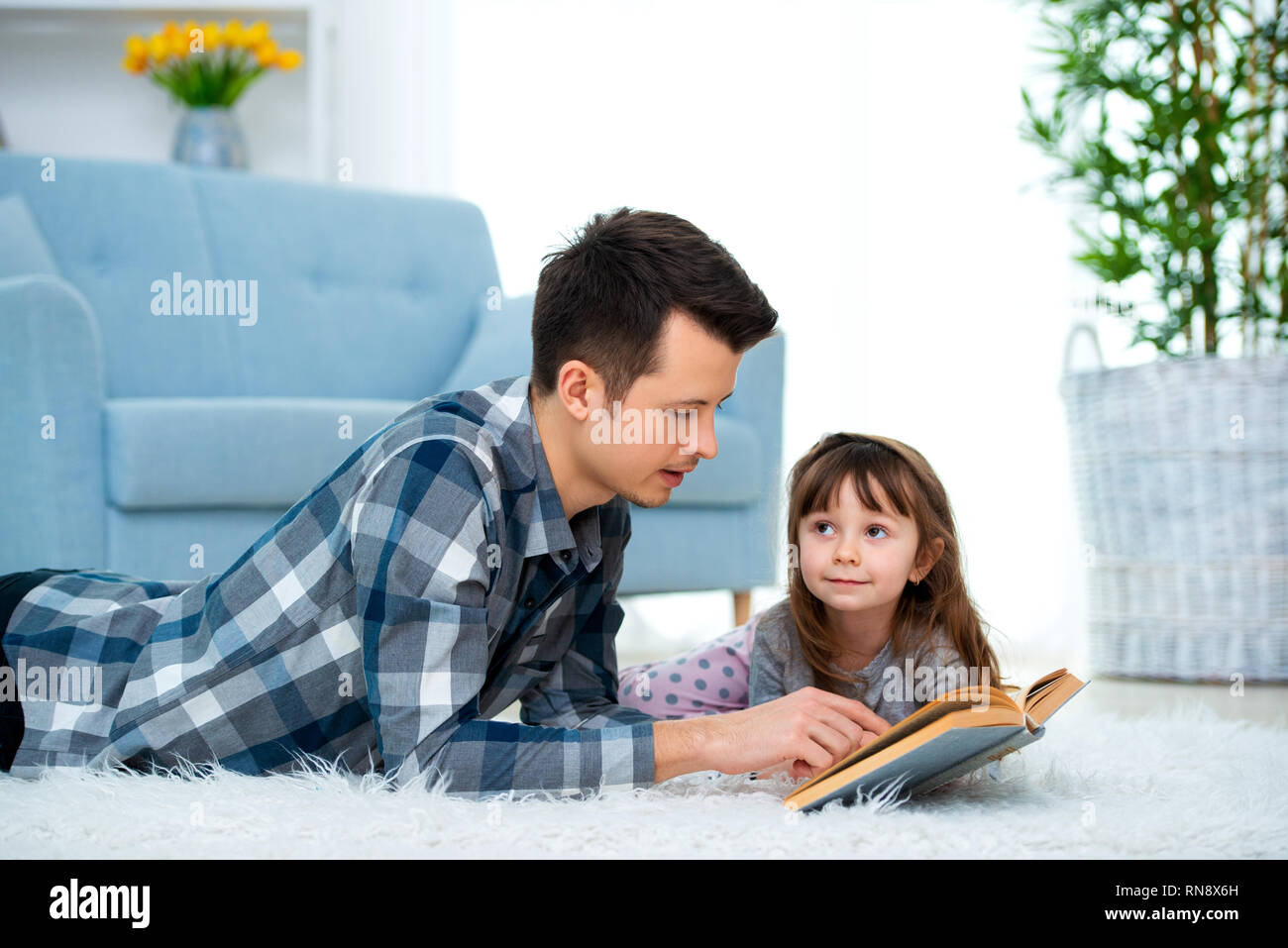 Cute little girl listening to dad reading fairy tale lying on warm ...