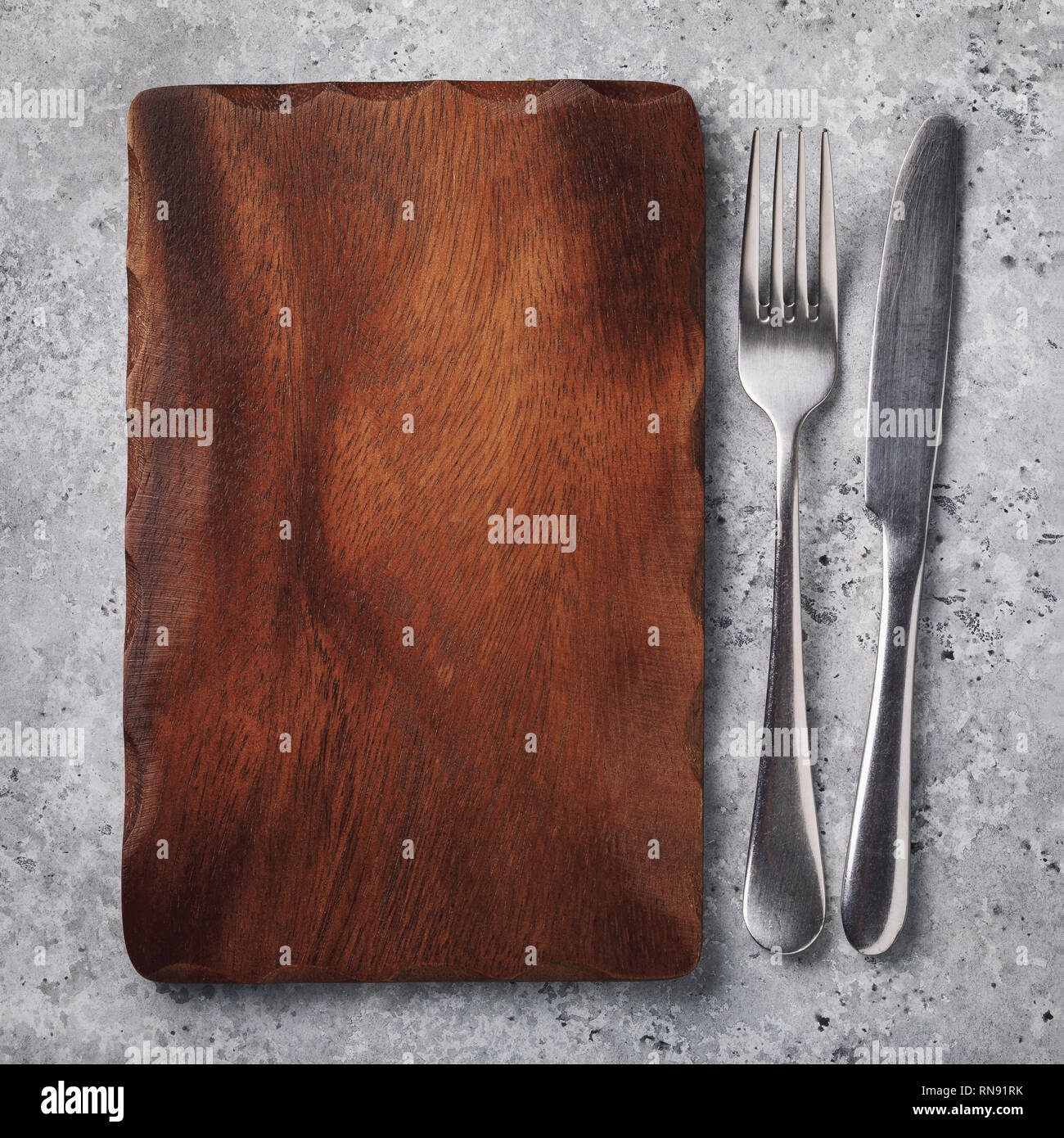 Empty wooden stand and cutlery on the table, top view. Food background ...